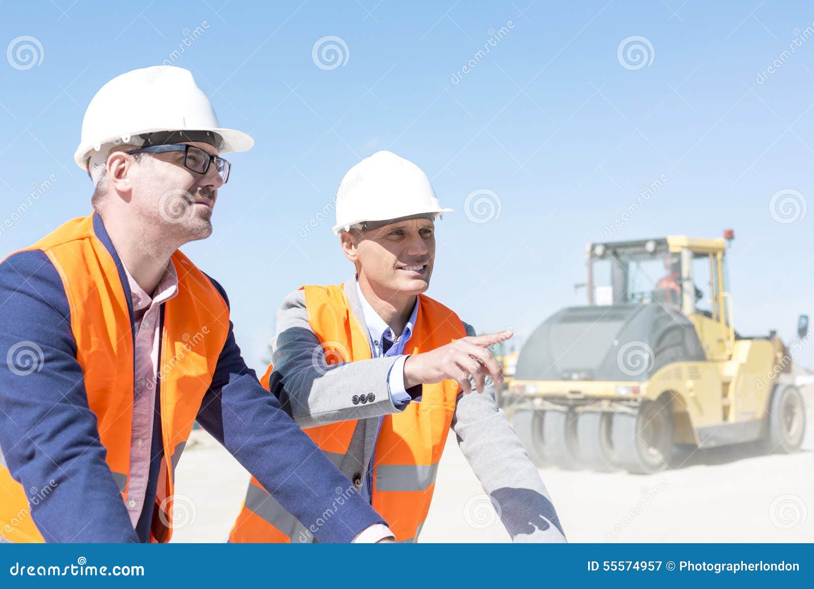 Supervisor Explaining Plan To Colleague at Construction Site Against ...