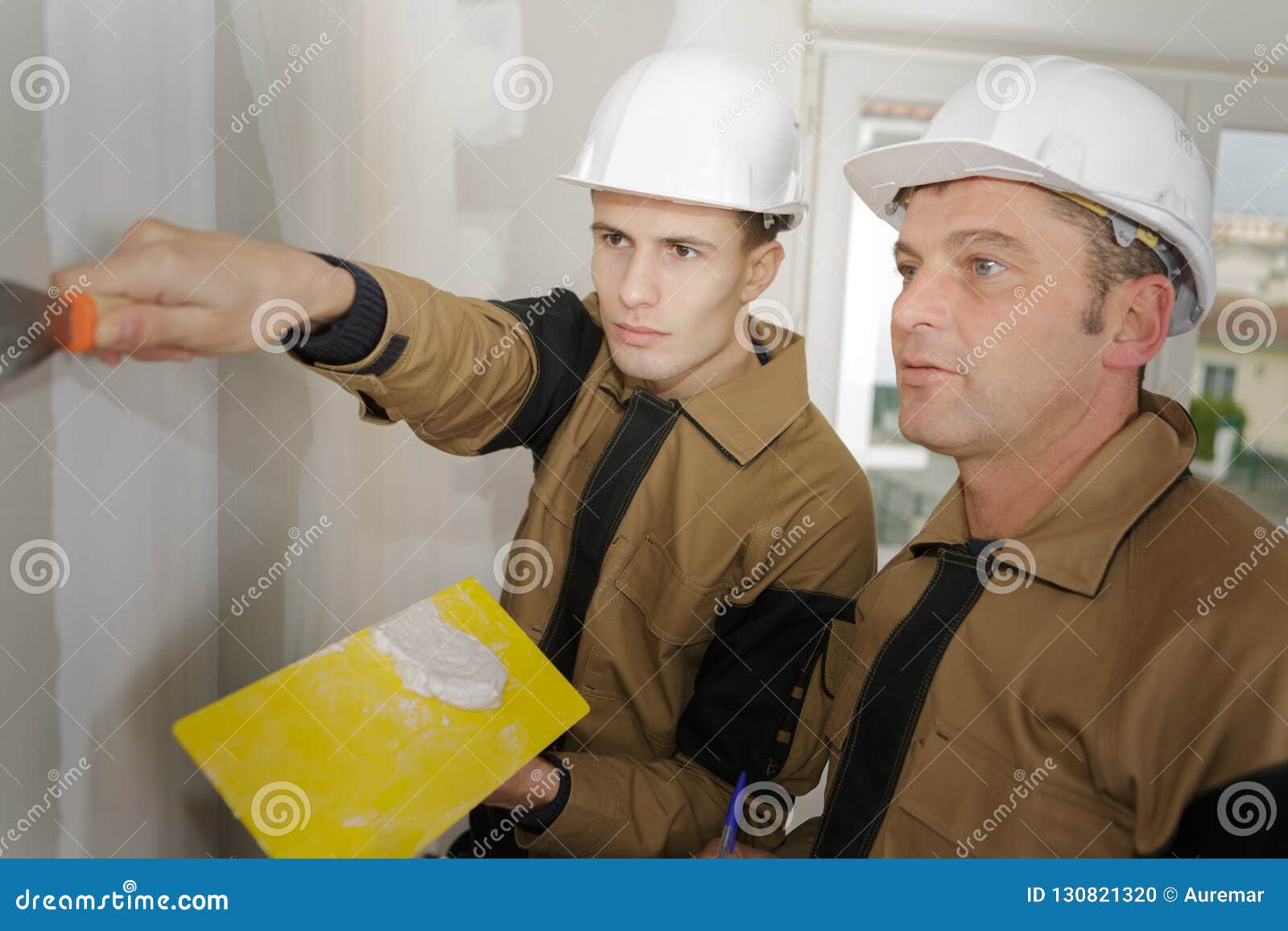 Supervisor Overseeing Apprentice Using Filler on Plasterboard Stock ...