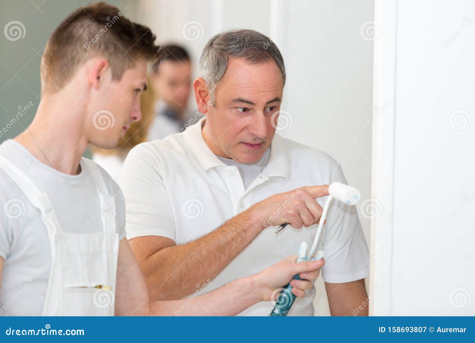 Supervisor Talking To Apprentice Using Paint Roller Stock Image - Image ...