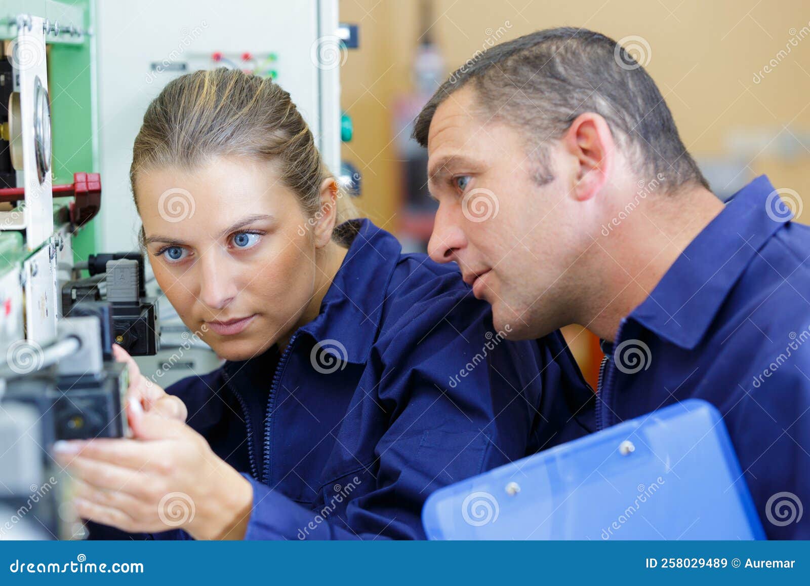 Supervisor Watching Over Female Apprentice Setting Up Machine Stock ...