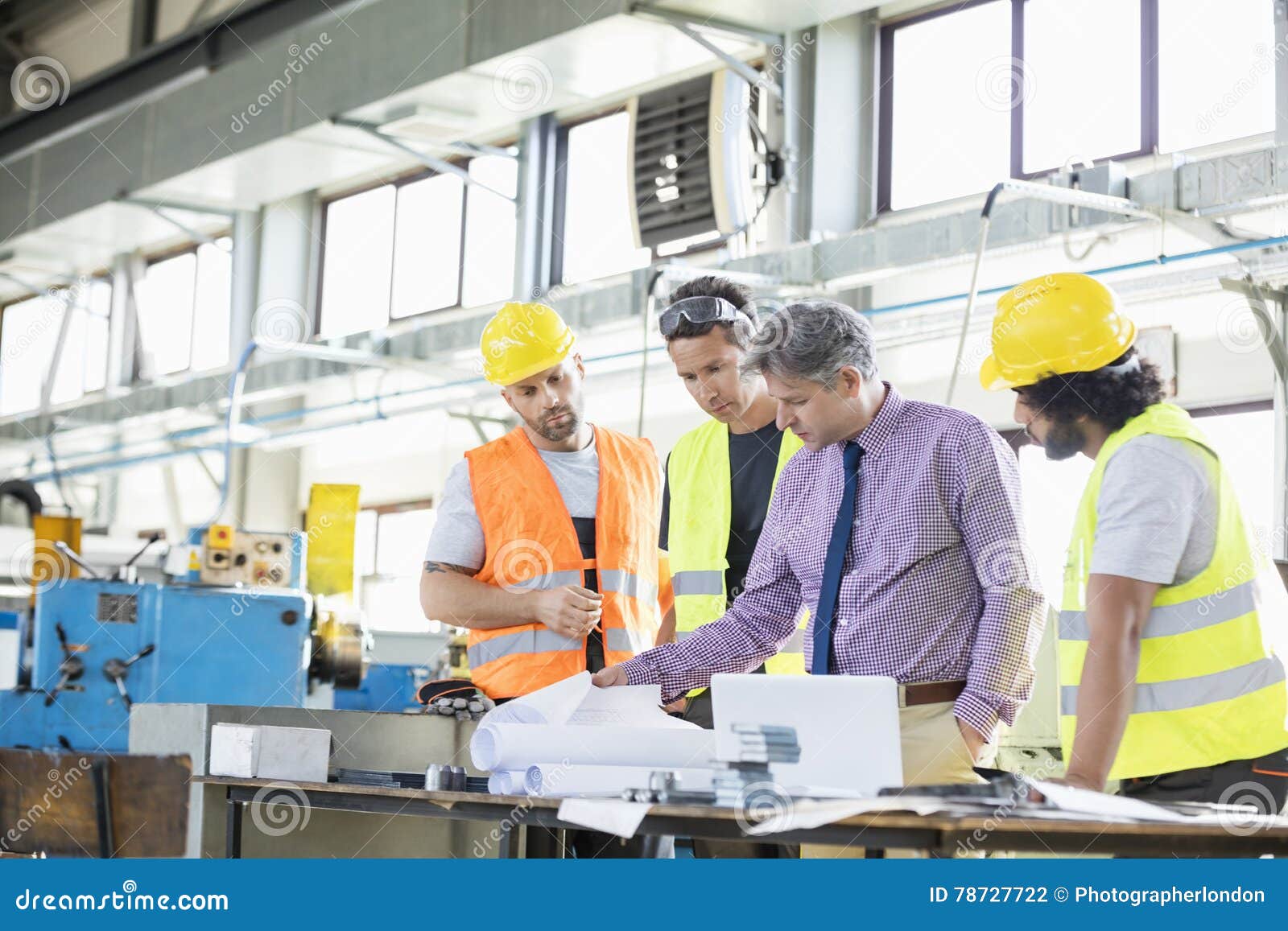 Supervisor with Workers Examining Blueprints at Table in Industry Stock ...