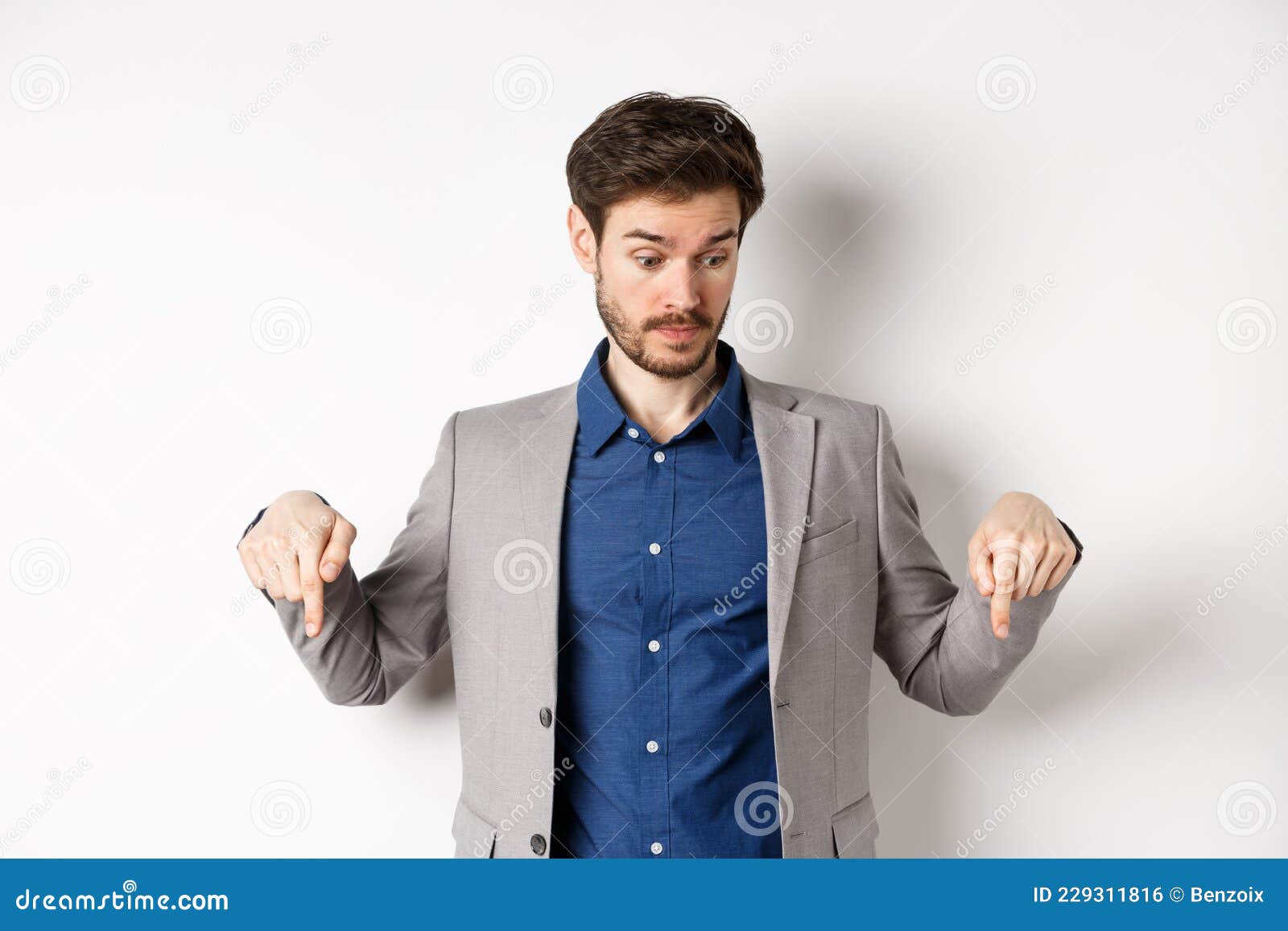 Surprised Businessman Looking and Pointing Down with Raised Eyebrows ...
