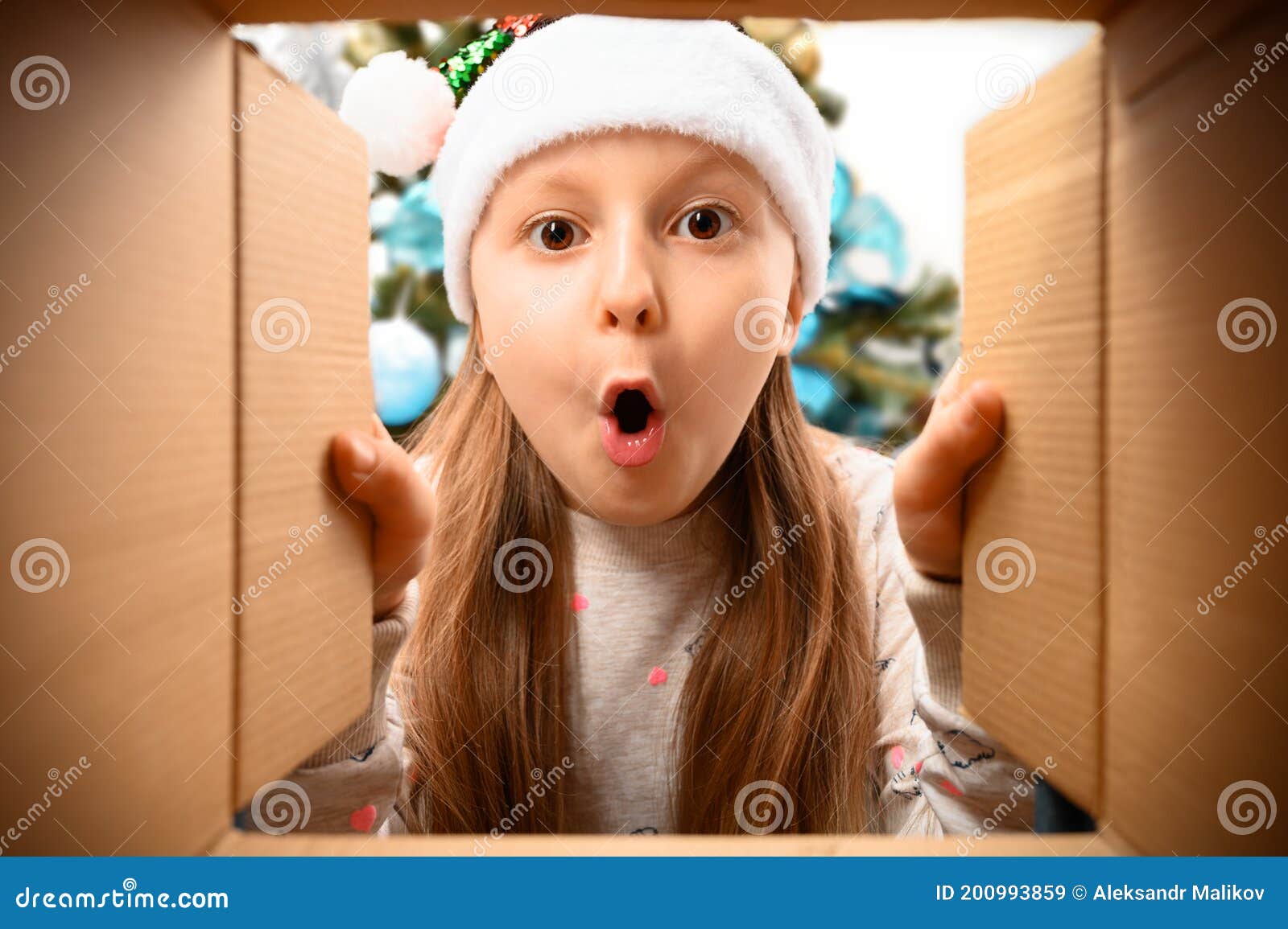 A Surprised Child Opens a New Year`s Gift on the Background of a ...