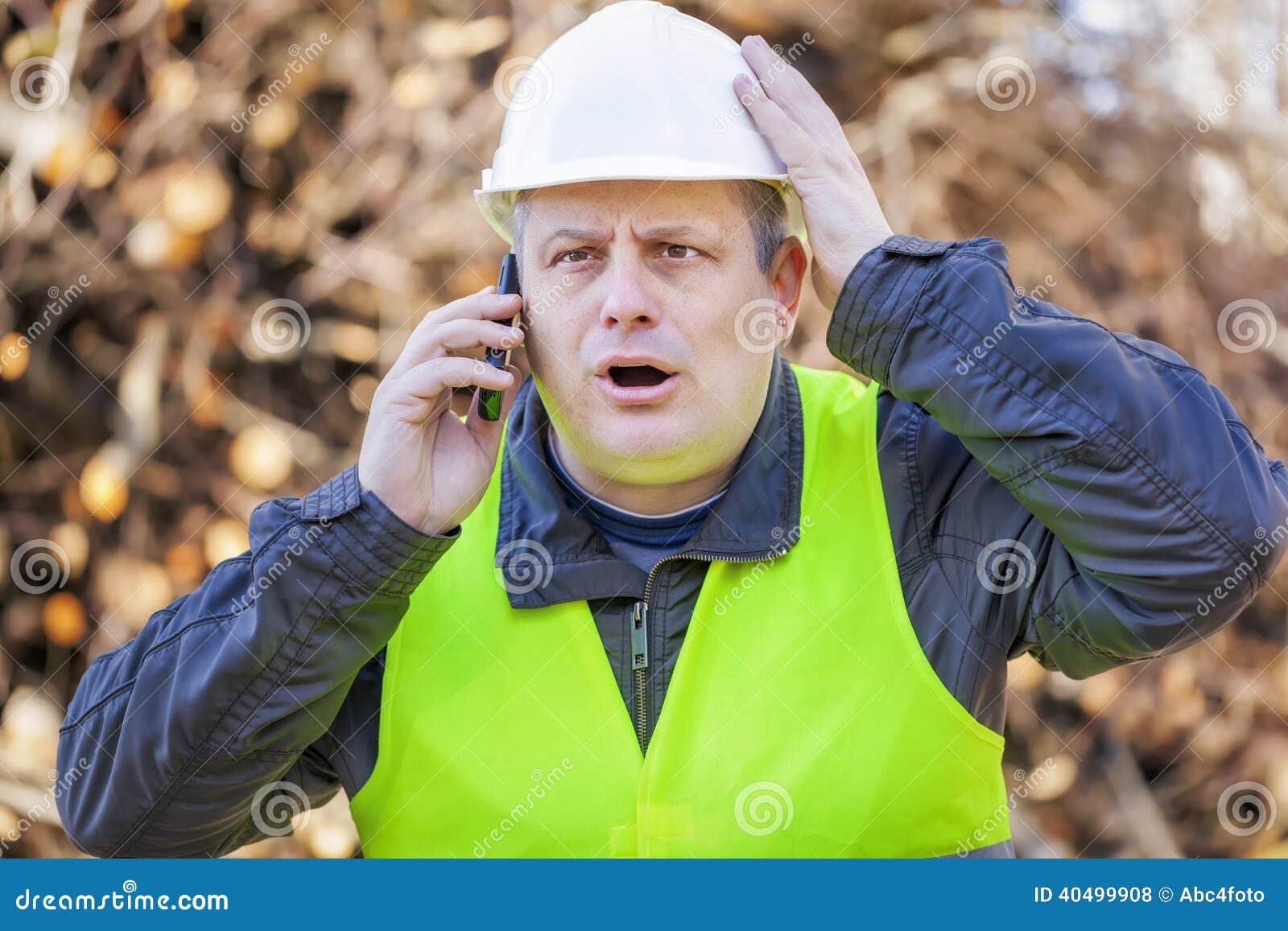 Surprised Worker In His 50s With Helmet Standing Outside And Holding A ...