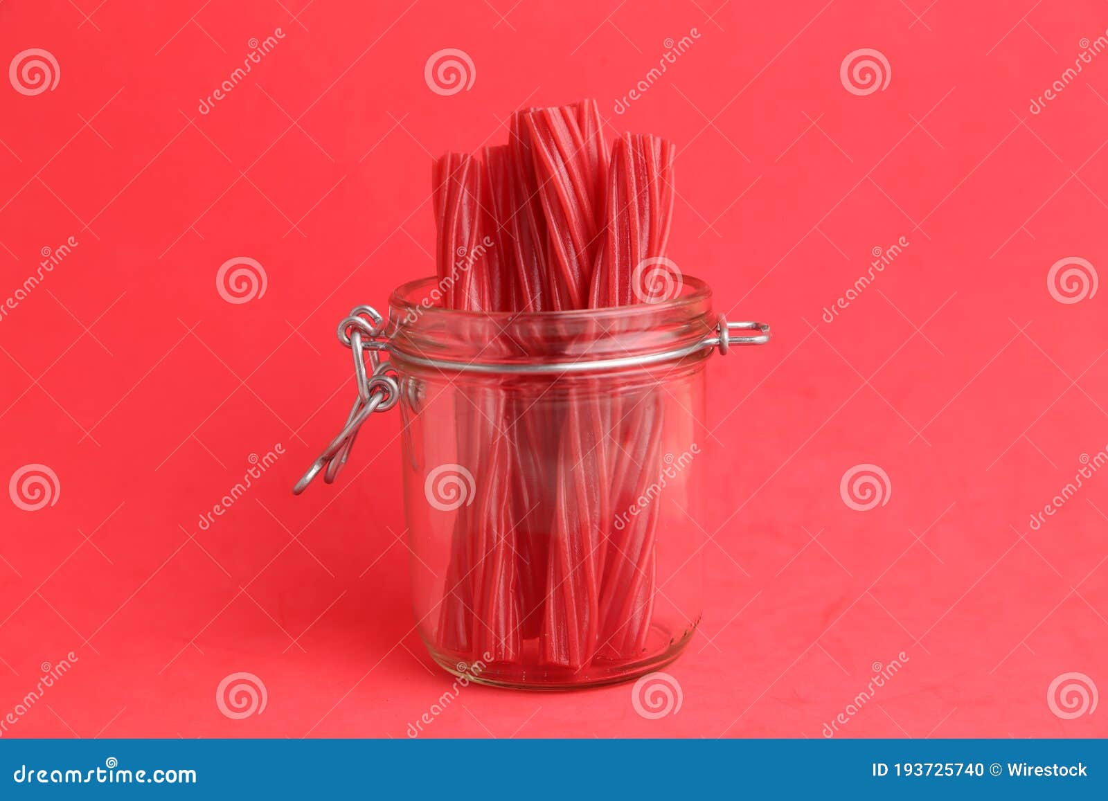 Sweet Red Candy Sticks in the Glass Jar on the Red Surface Stock Photo ...