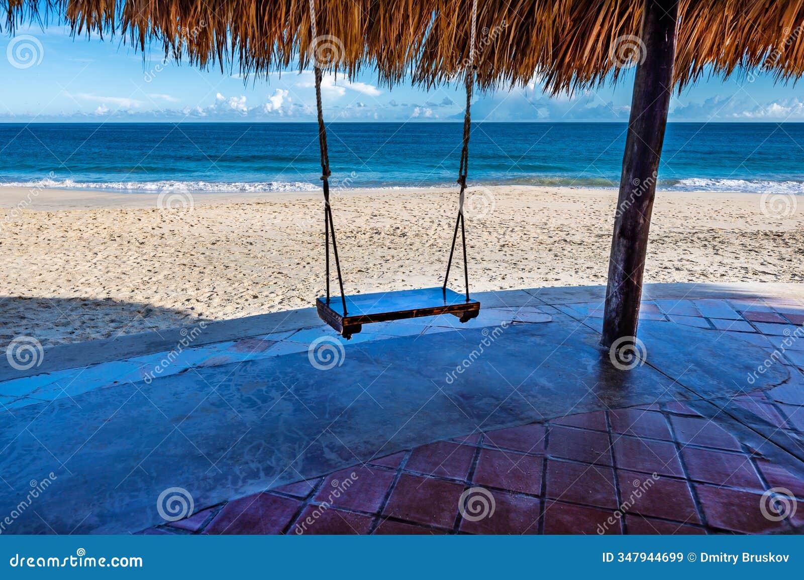 A Swing is Hanging from a Thatched Roof Over a Beach Stock Image ...