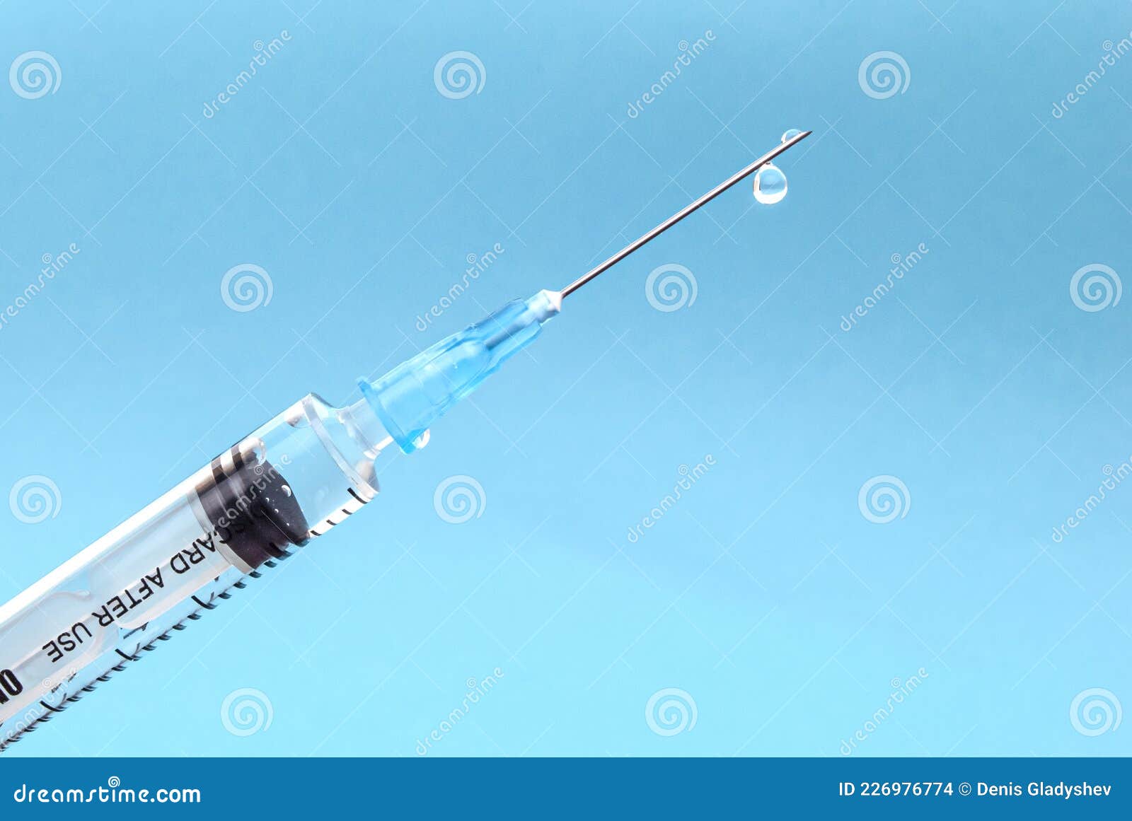 Syringe with a Drop of Medication at the End of the Needle on a Blue ...