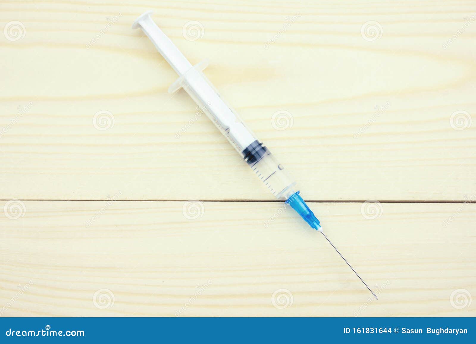 Syringe on a wooden table stock photo. Image of wooden - 161831644