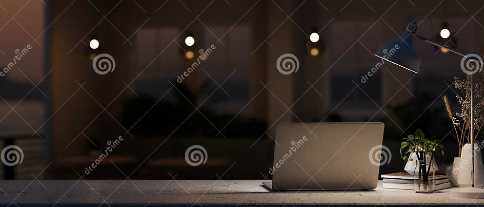 A Table Features a Laptop Computer and a Dim Light from a Lamp in a ...