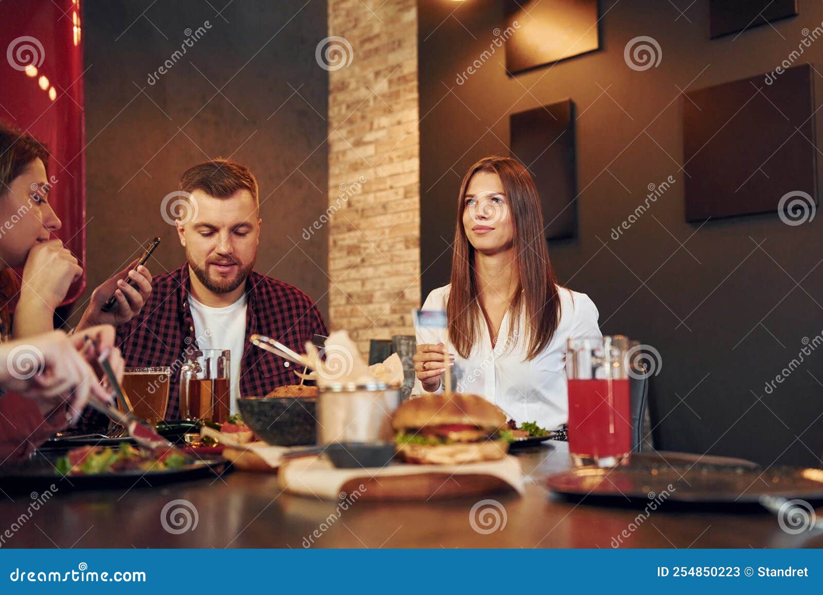By the Table. Group of Young Friends Sitting Together in Bar with Beer ...