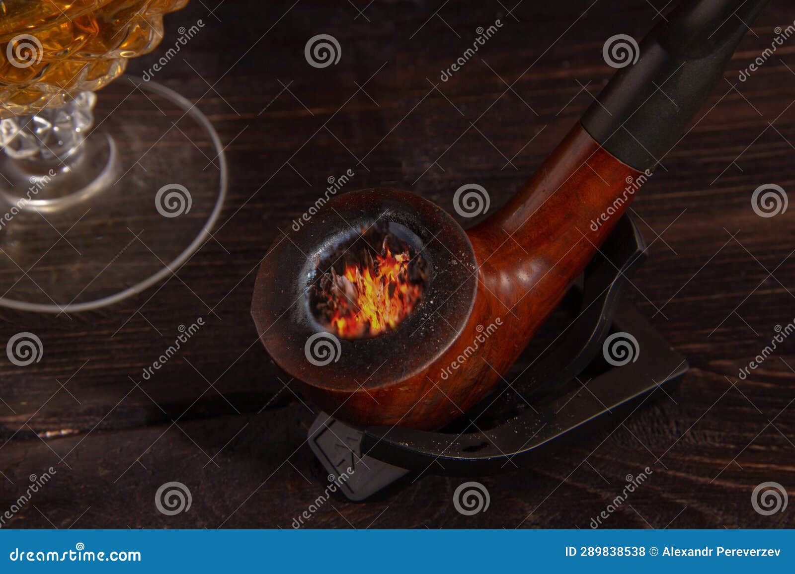 On the Table There is a Glass of Whiskey and a Lighted Smoking Pipe ...