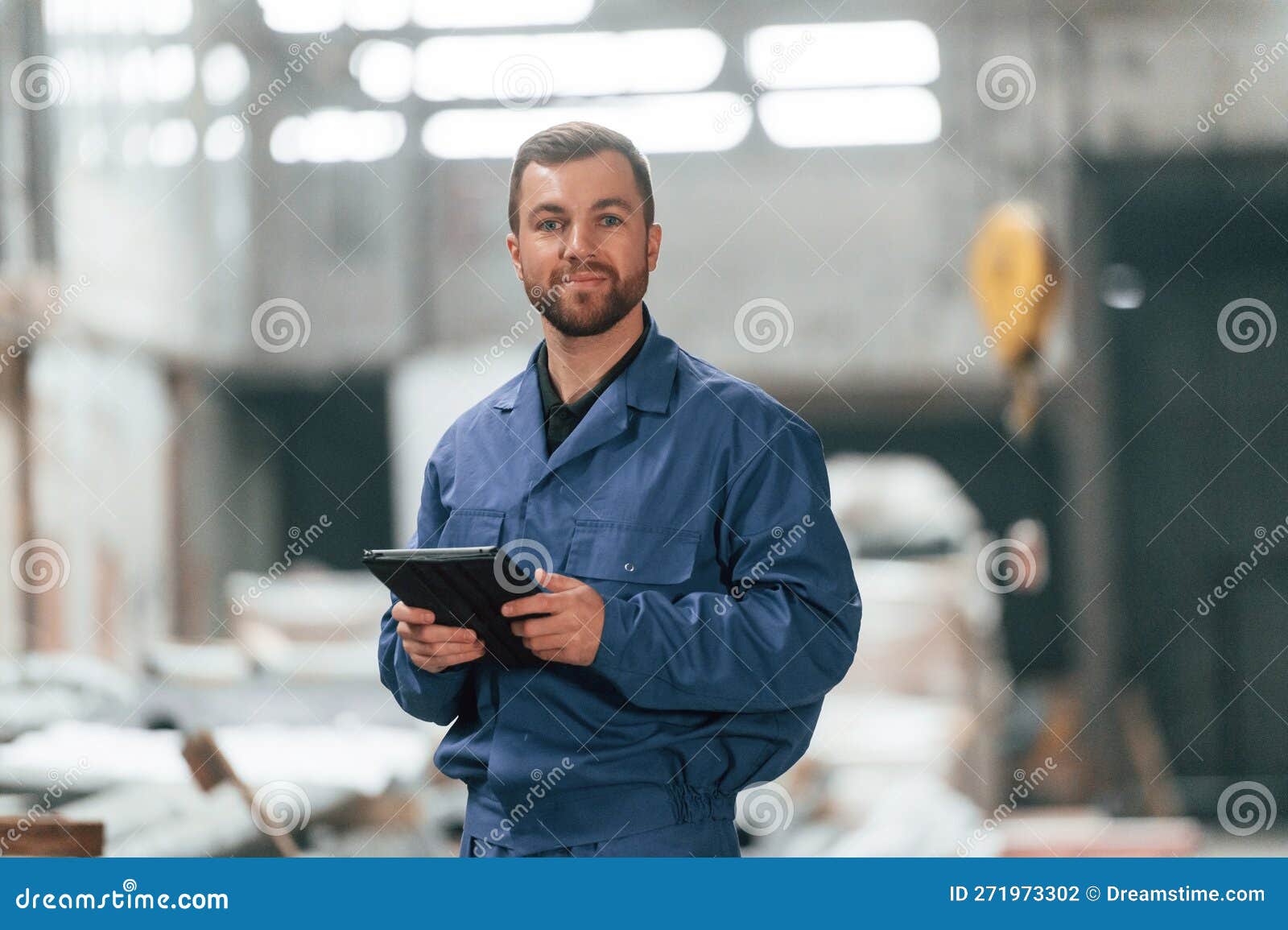 With Tablet in Hands. Factory Worker in Blue Uniform is Indoors Stock ...