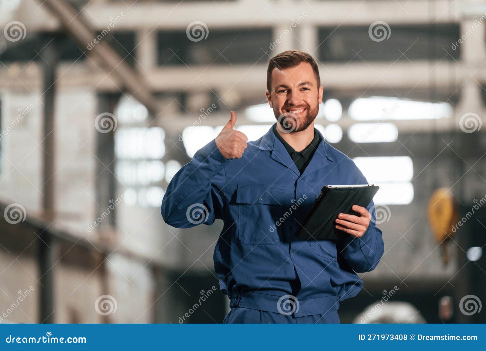 With Tablet in Hands. Factory Worker in Blue Uniform is Indoors Stock ...