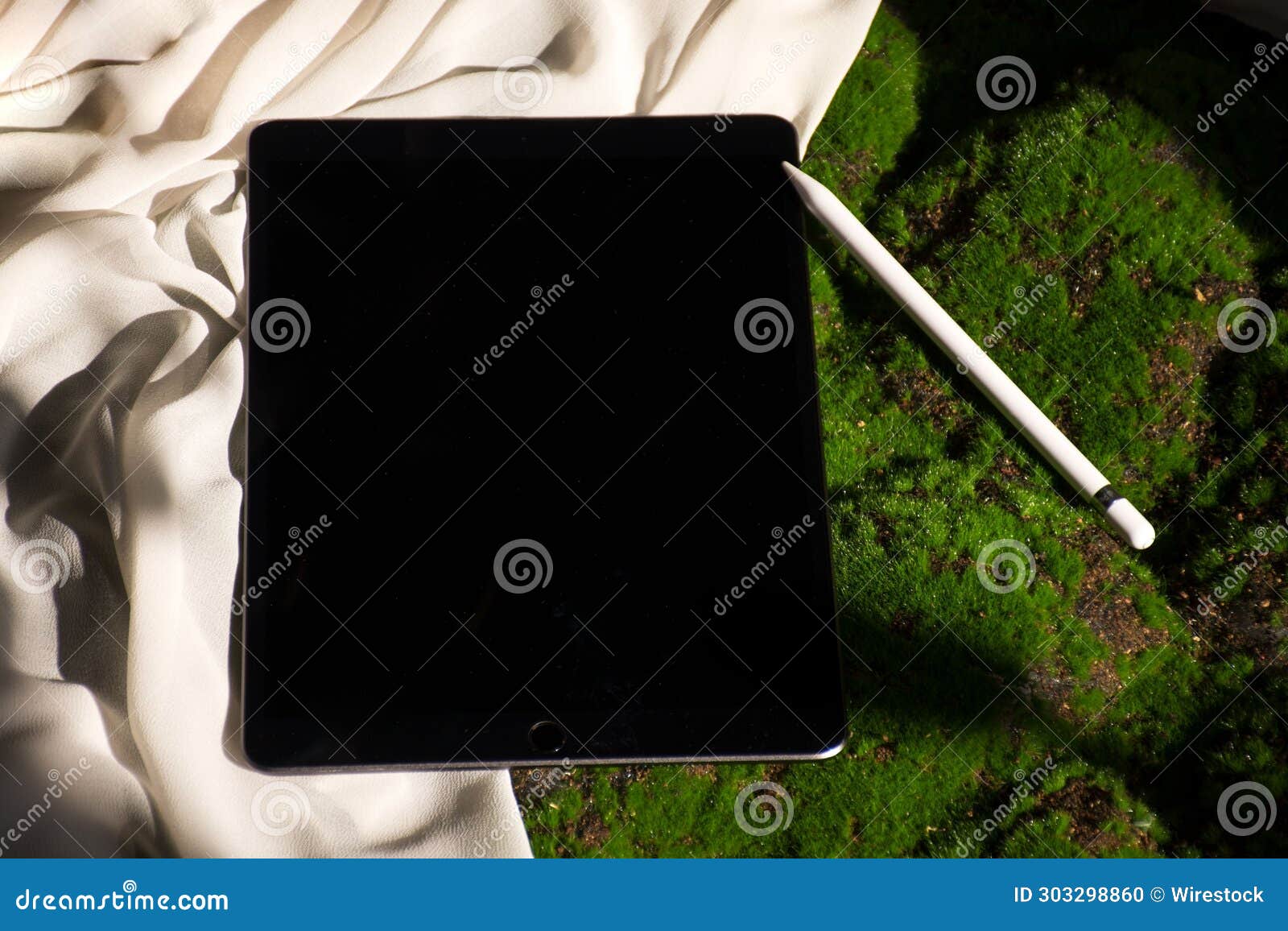 A Tablet that is Lying on Some Cloth Next To an Object Stock Photo ...
