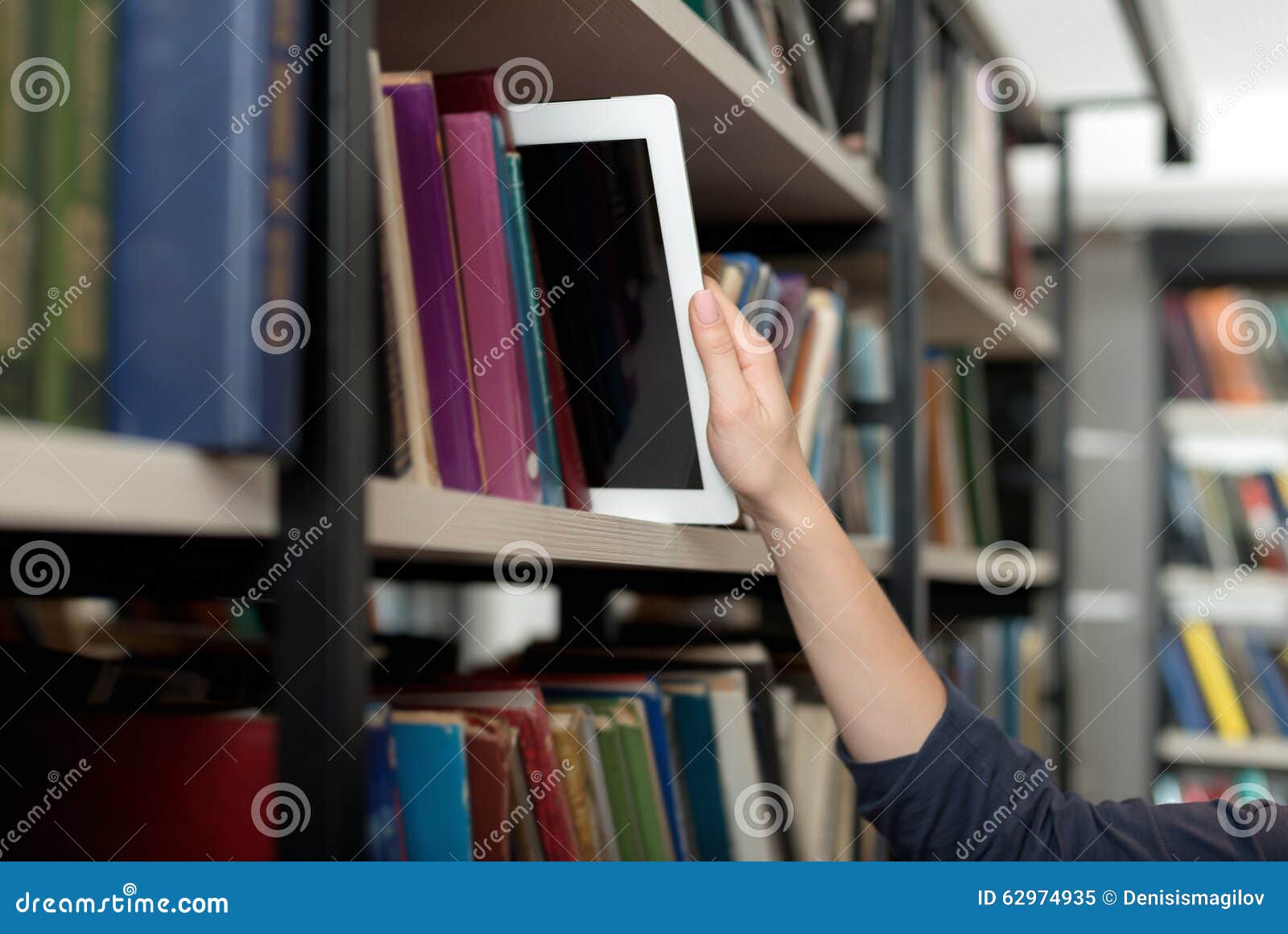 A Tablet Picked with a Hand from a Book Shelf in the Library Stock ...