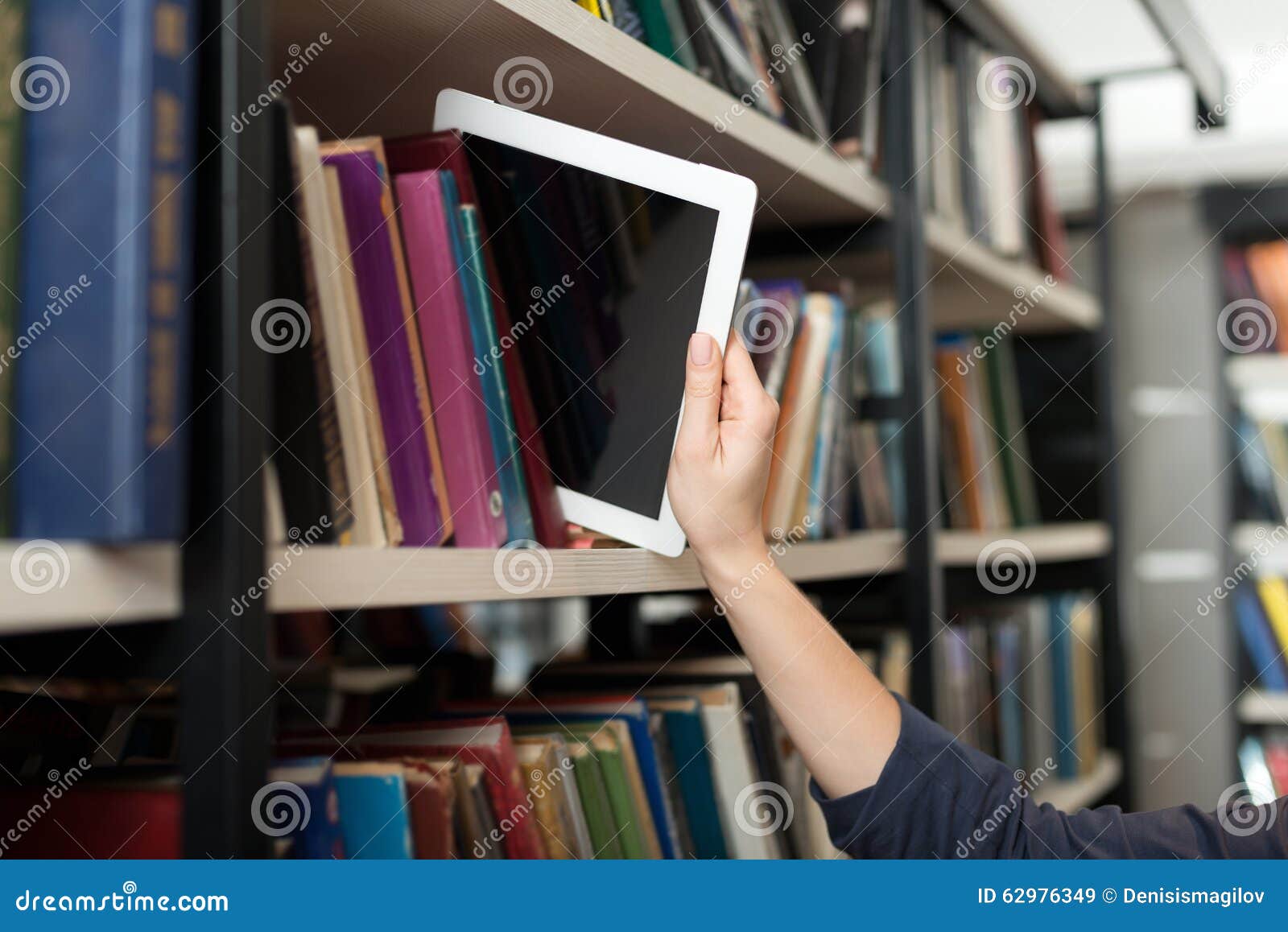 A Tablet Put with a Hand on a Book Shelf in the Library, a Conce Stock ...