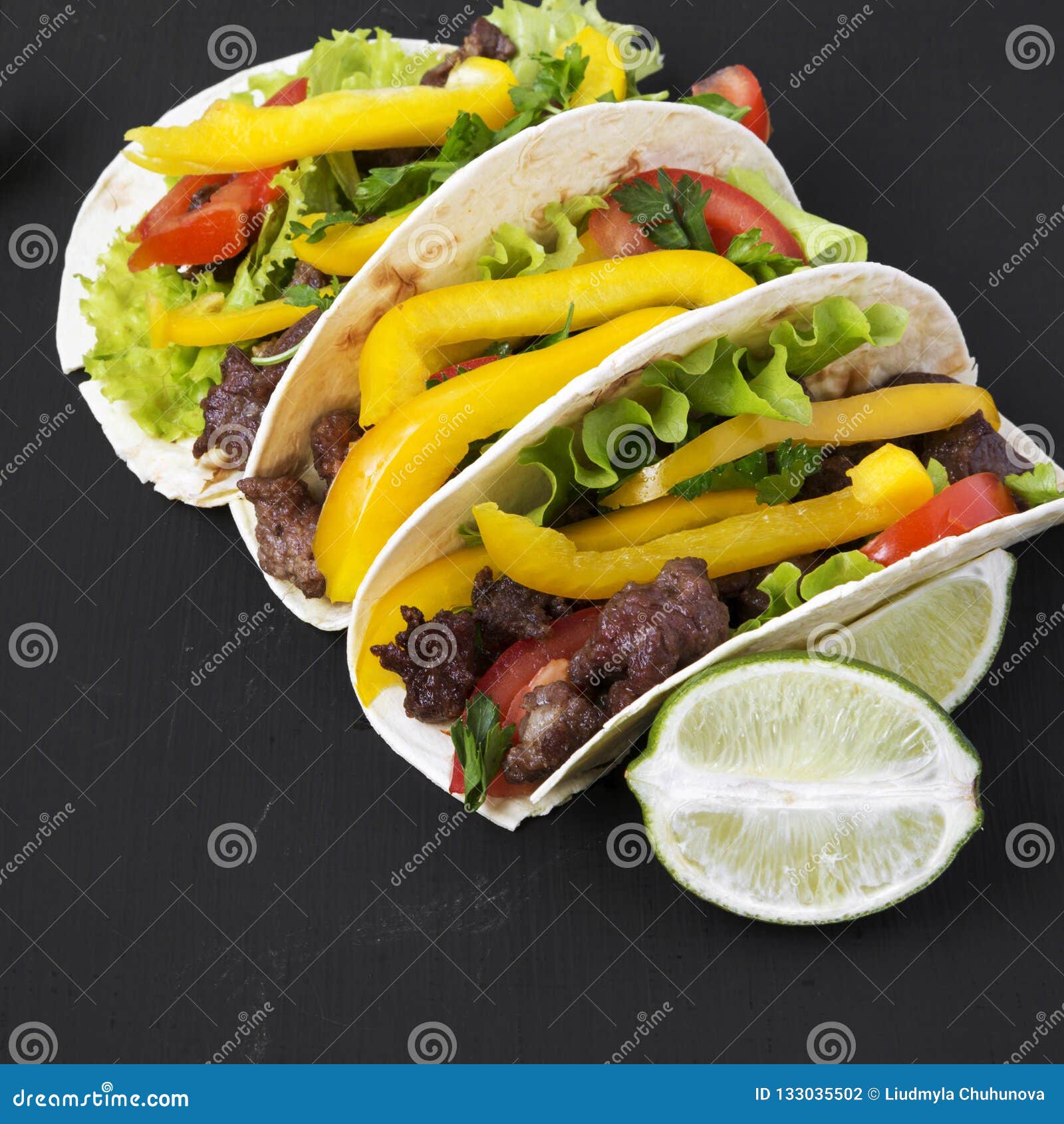 Tacos with Beef and Vegetables and Lime on a Black Surface, Side View ...