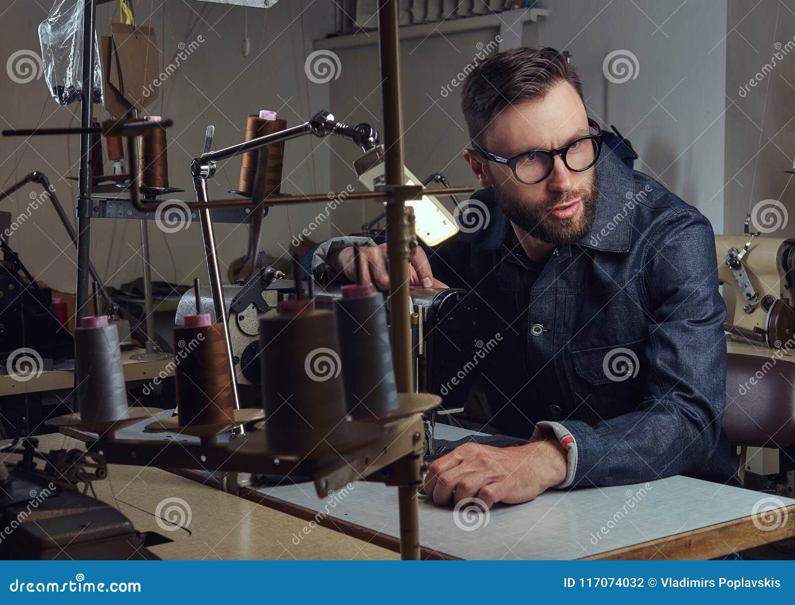 Tailor Sitting at Table with Sewing Machine and Looking at a Camera in ...