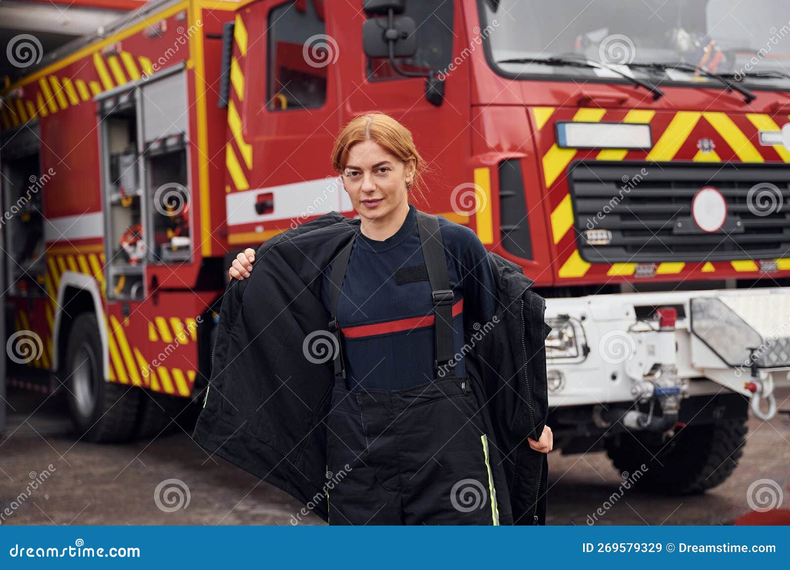 Taking Off the Protective Clothes. Woman Firefighter in Uniform is at ...