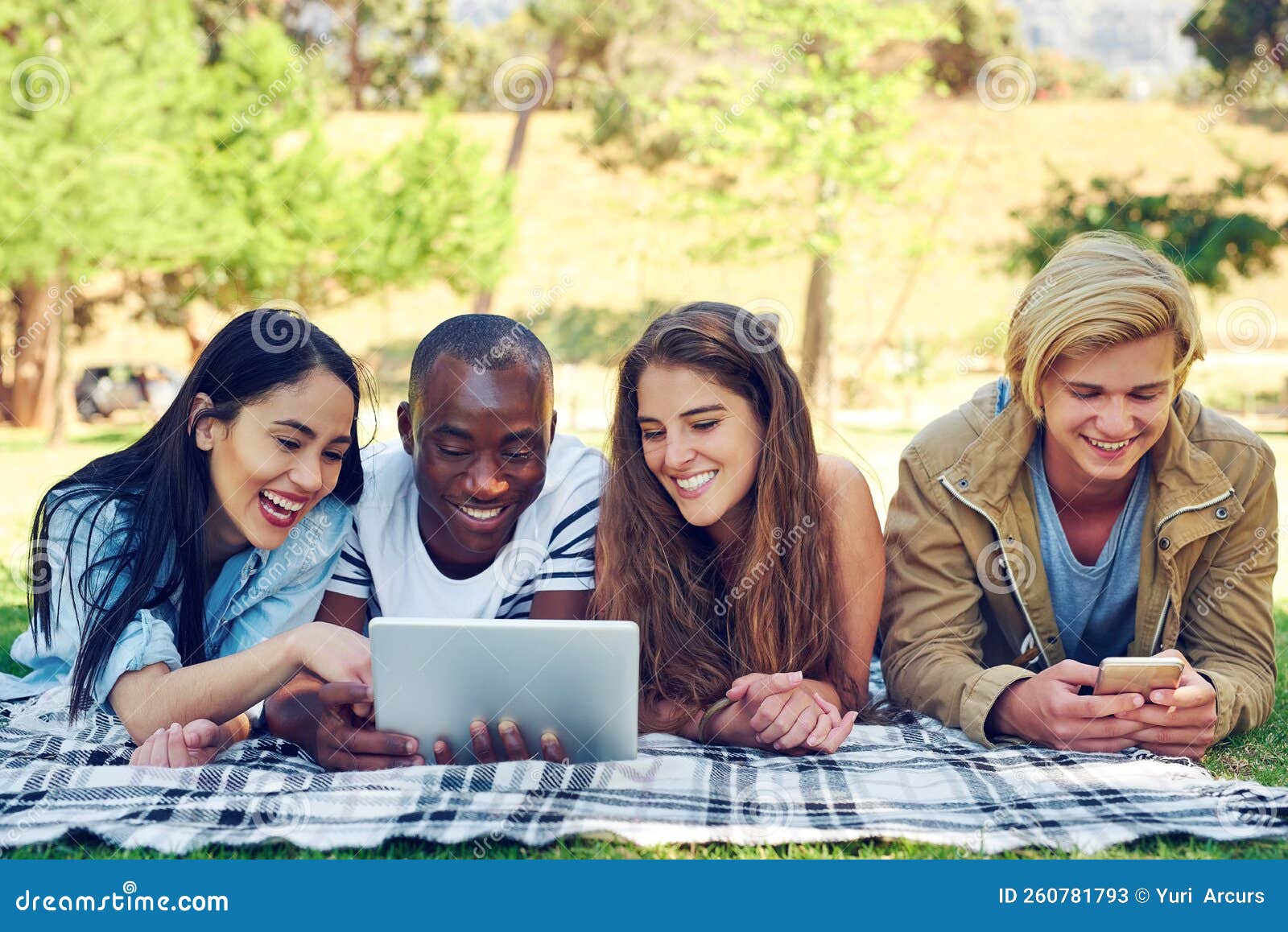 Taking Technology To the Park. a Group of Young Friends Relaxing on a ...