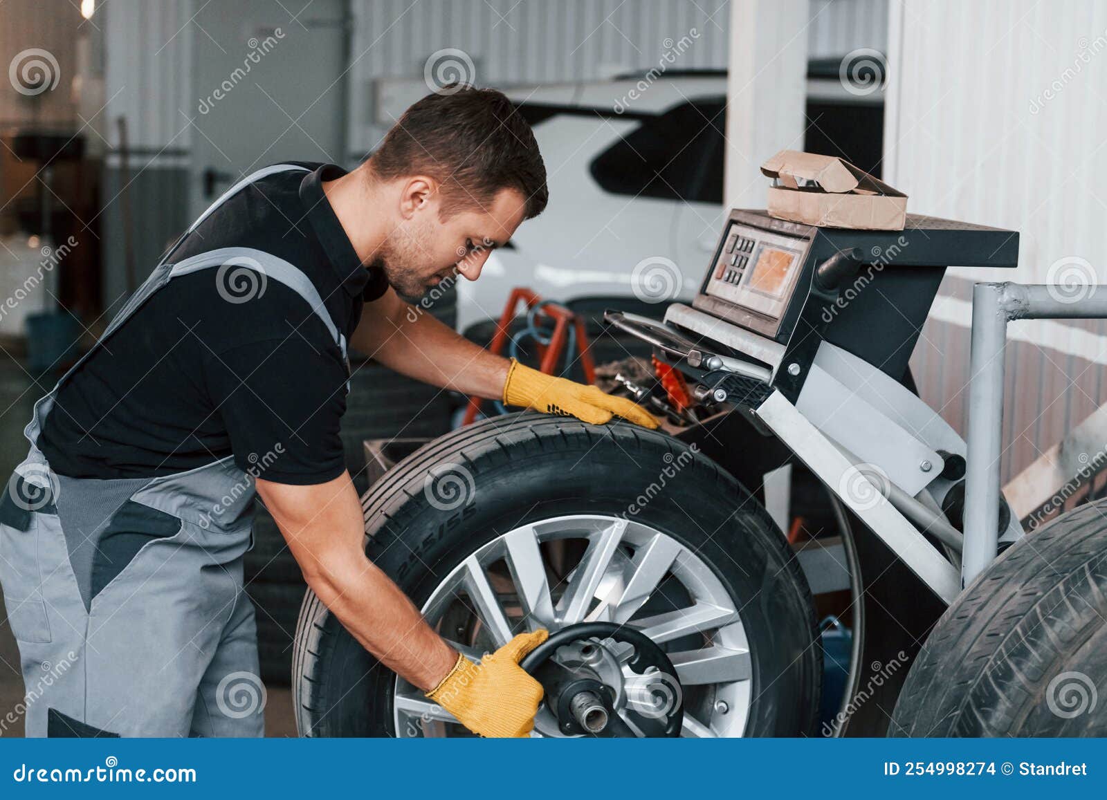 Taking the Wheel. Man in Uniform is Working in the Auto Service Stock ...