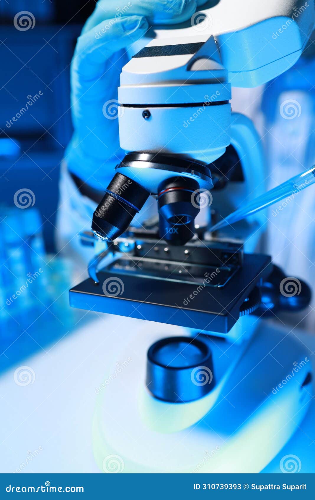 A Talented Scientist Sits in His Lab while Using a Microscope To Look ...