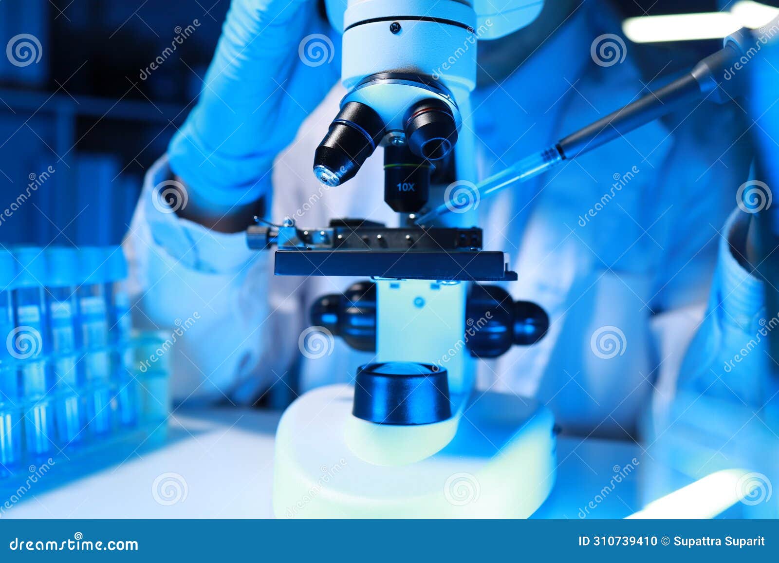 A Talented Scientist Sits In His Lab While Using A Microscope To Look ...