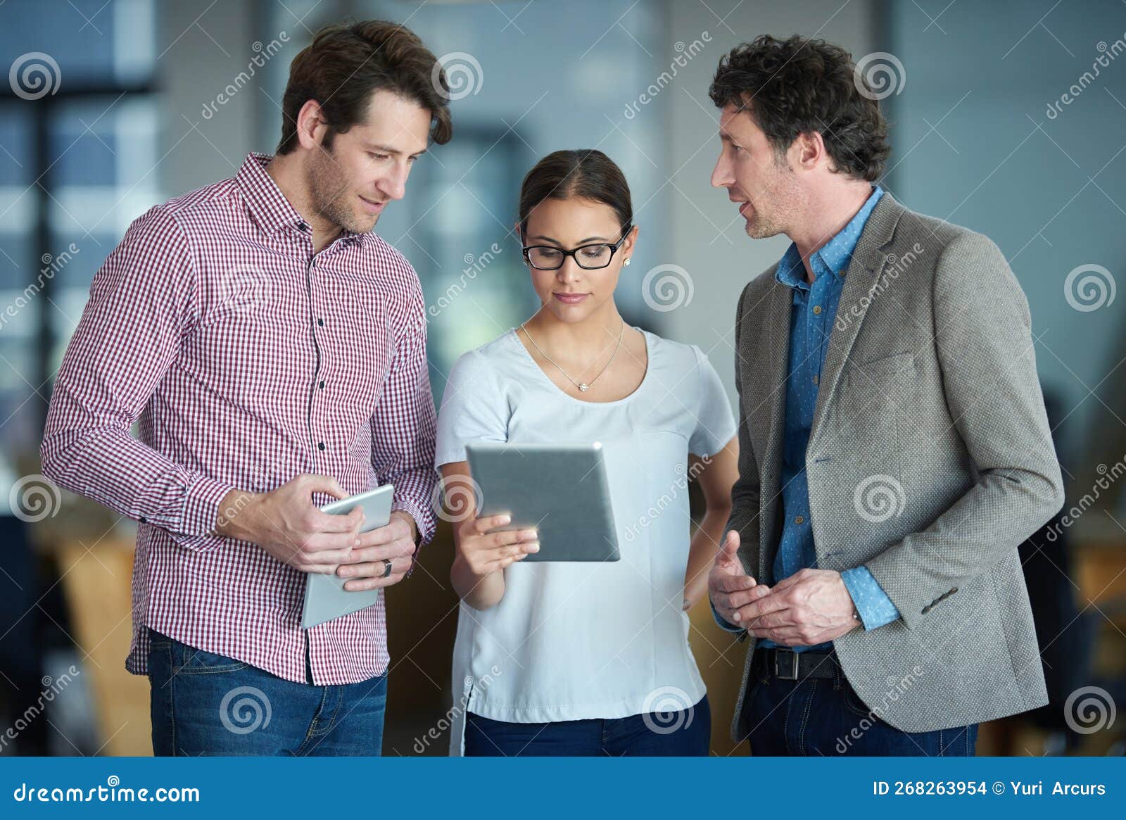 Talking Tech in the Office. Three Colleagues Talking Together Over a ...