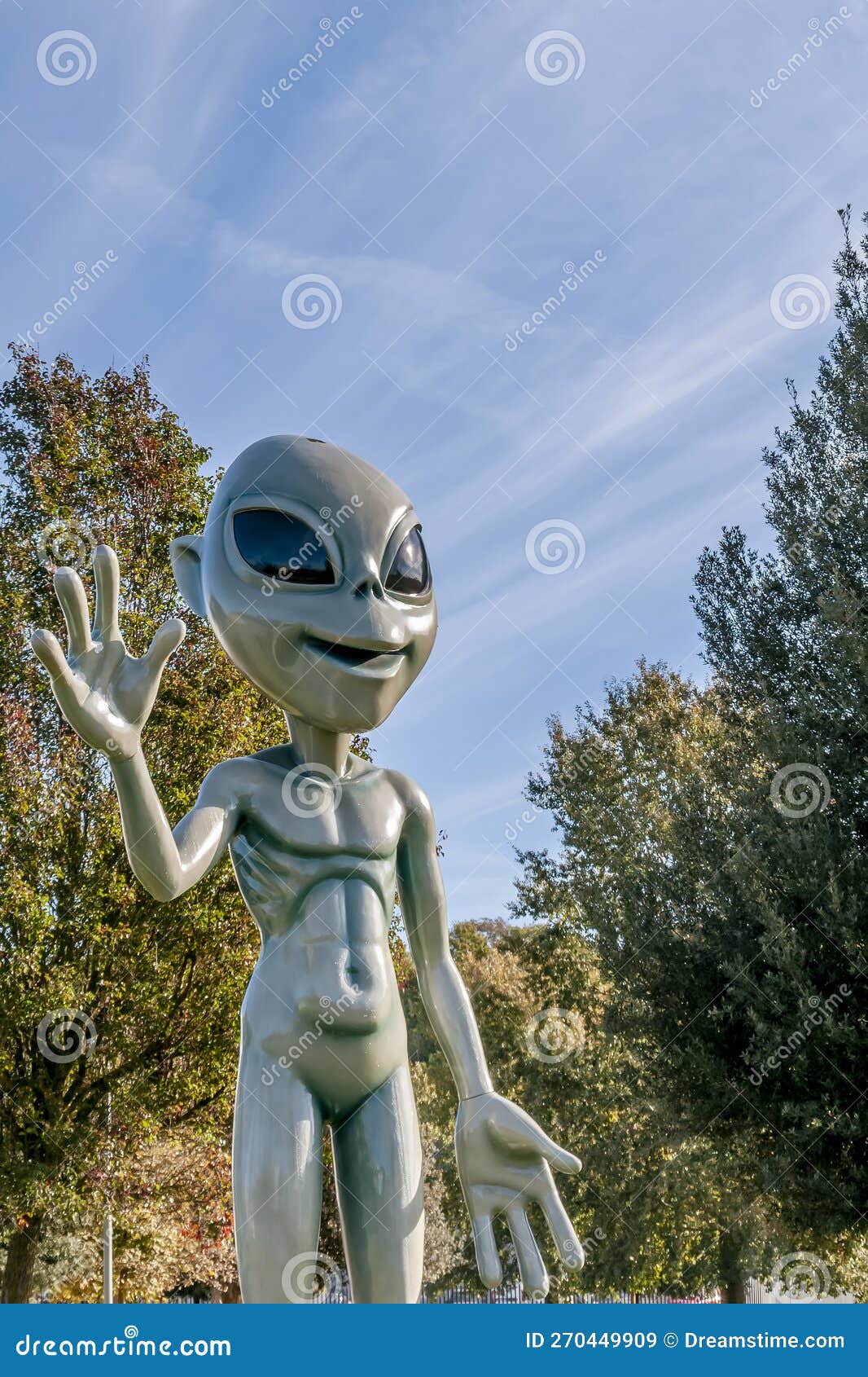 A Large Alien Waves with a Four-fingered Hand, Surrounded by Trees ...