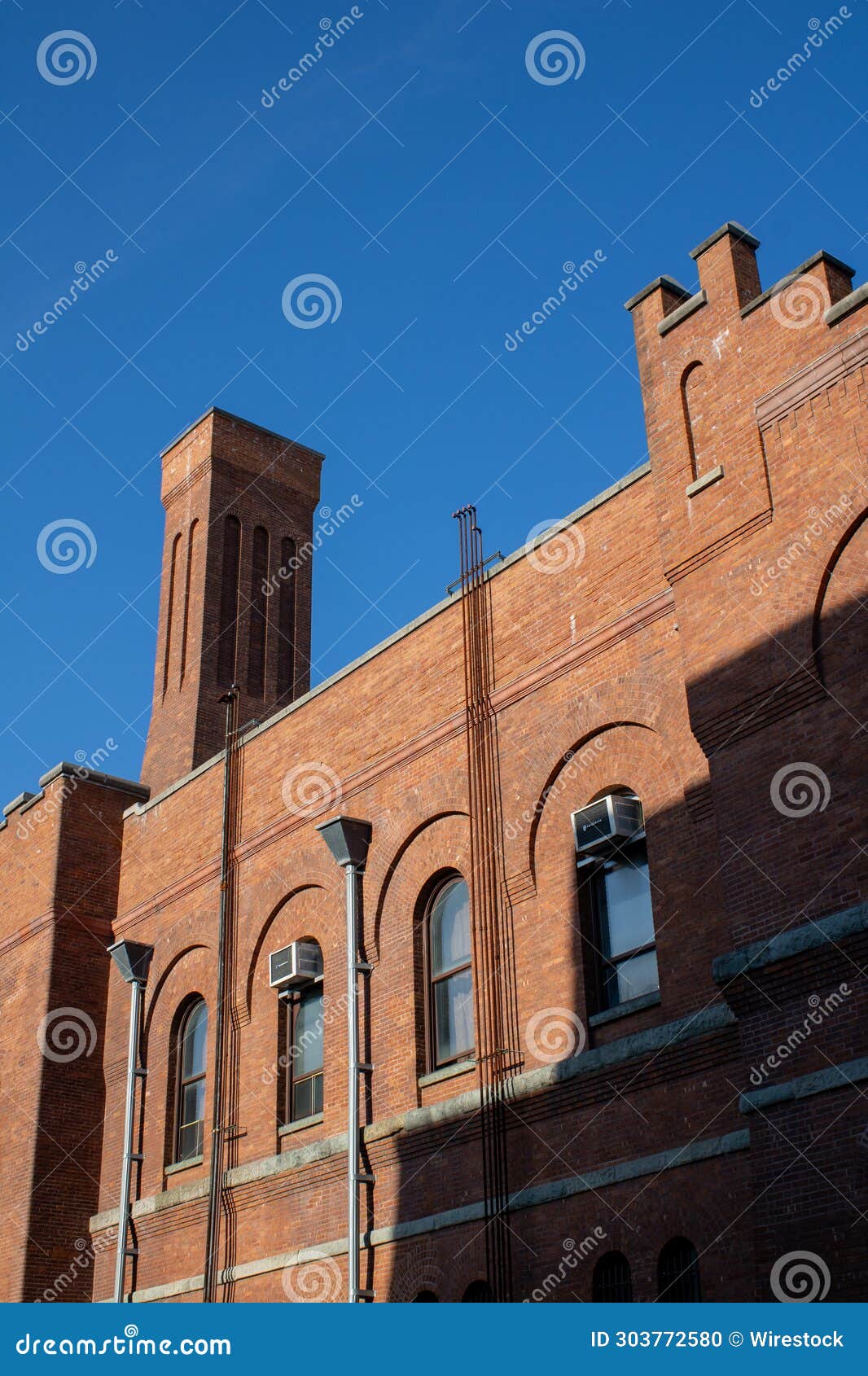 A Tall Brick Building with Two Clock Towers in Front of Blue Sky ...