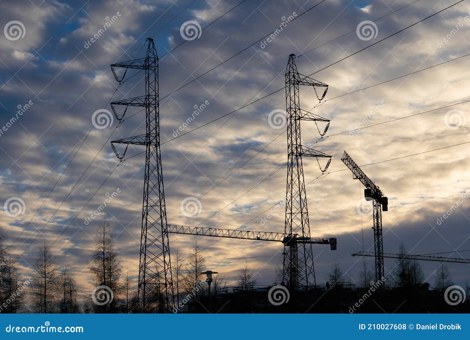 A Tall Construction Crane Against the Setting Sun. High Voltage Power ...