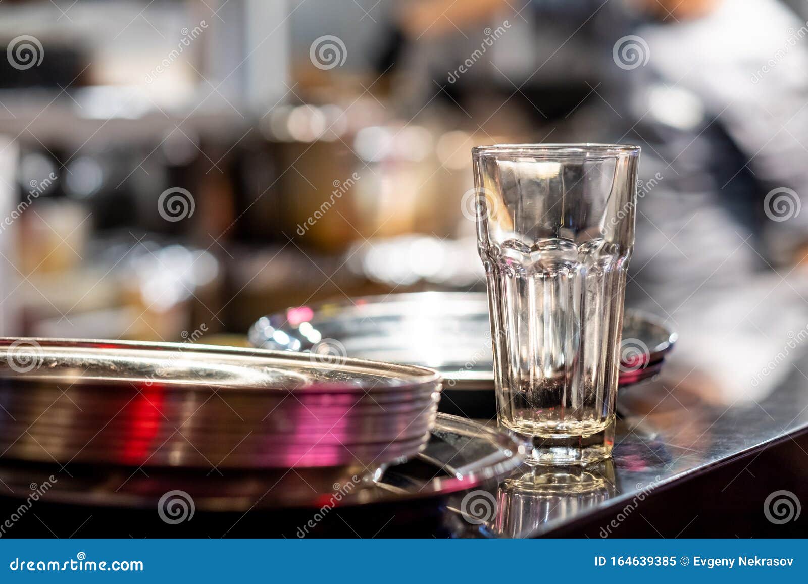 A Tall Empty Glass Water Glass and a Stack of Plates on a Table in a ...
