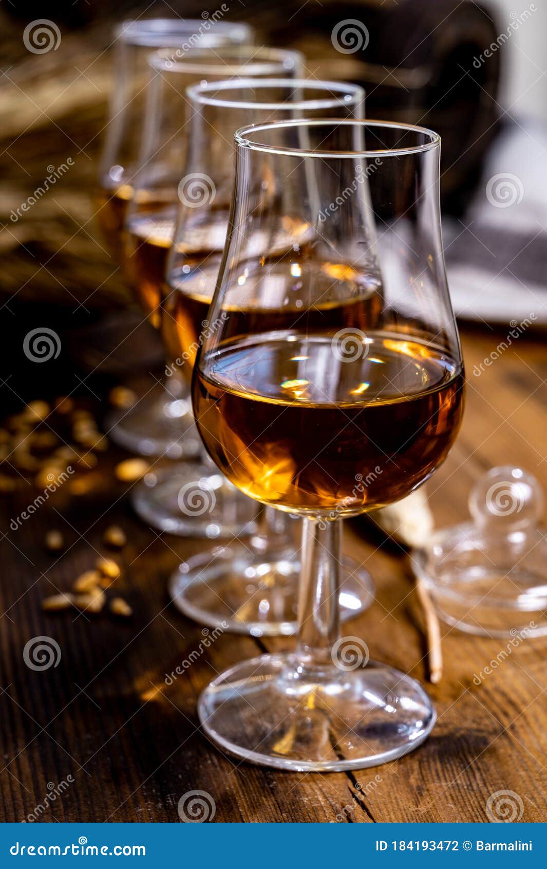 Tasting Glasses With Aged Scotch Whisky Or Bourbon On Old Dark Wooden Vintage Table With Barley