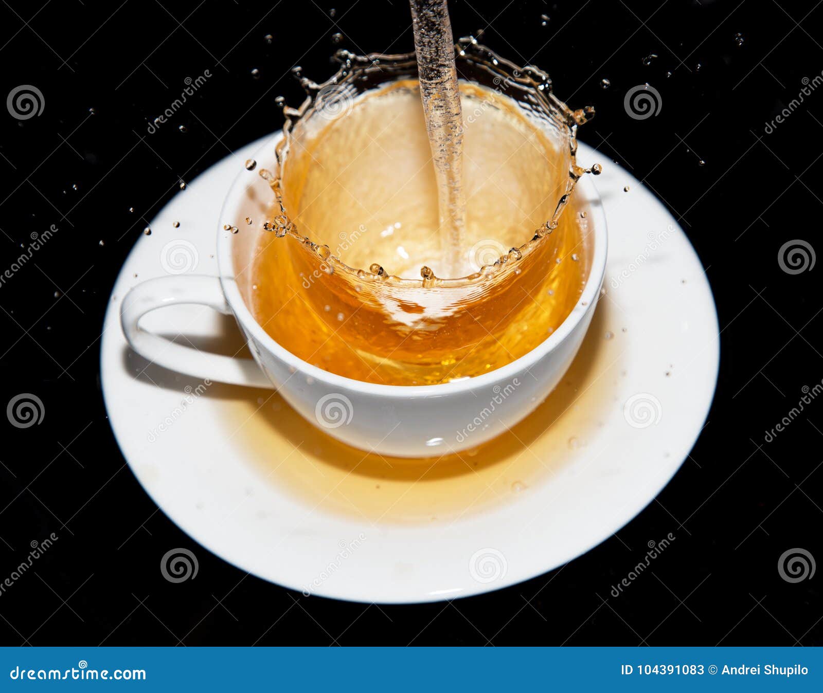 Tea Being Poured into a Saucer with Splashes on a Black Background ...