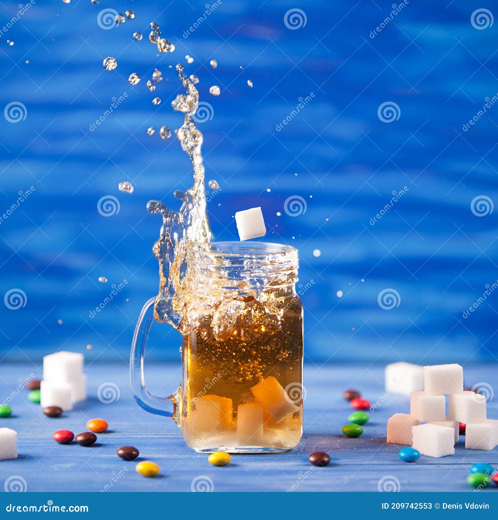 Tea Splash in Glass Cup Falling Sugar on Blue Table and Blue Background ...