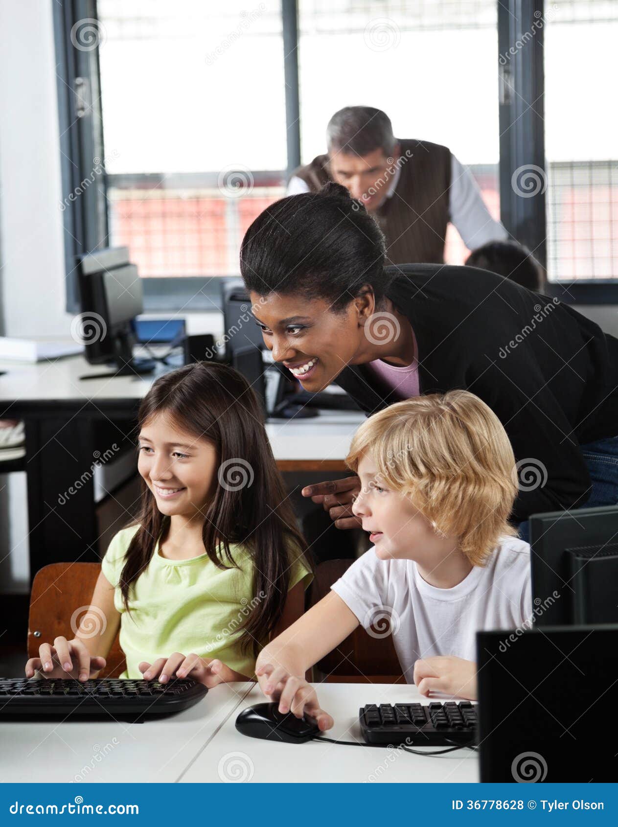 Teacher Assisting Schoolchildren in Using Desktop Stock Photo - Image ...