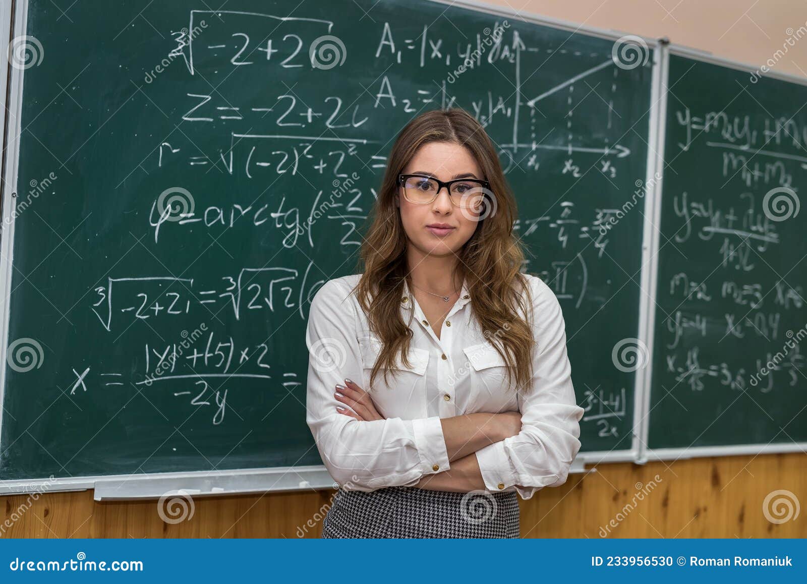 Teacher with Book Looking at Camera in Classroom. Math Formulas Write ...