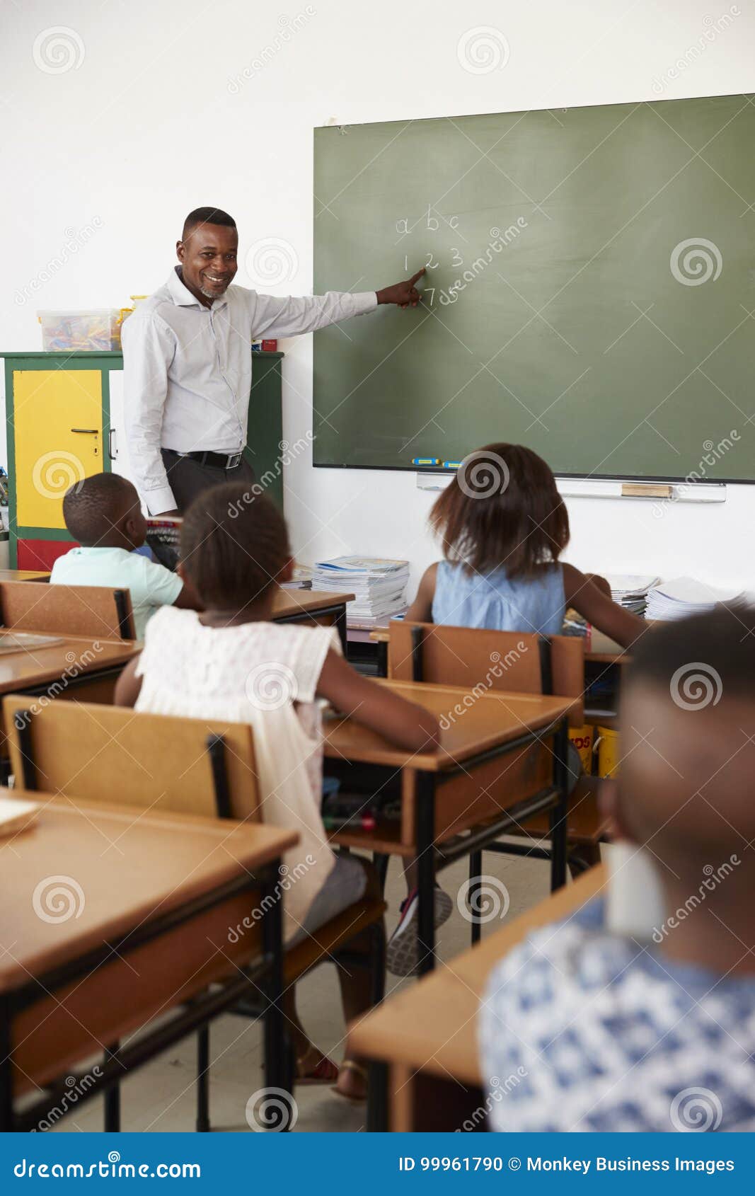 Teacher at Chalkboard in Elementary School Class, Vertical Stock Photo ...