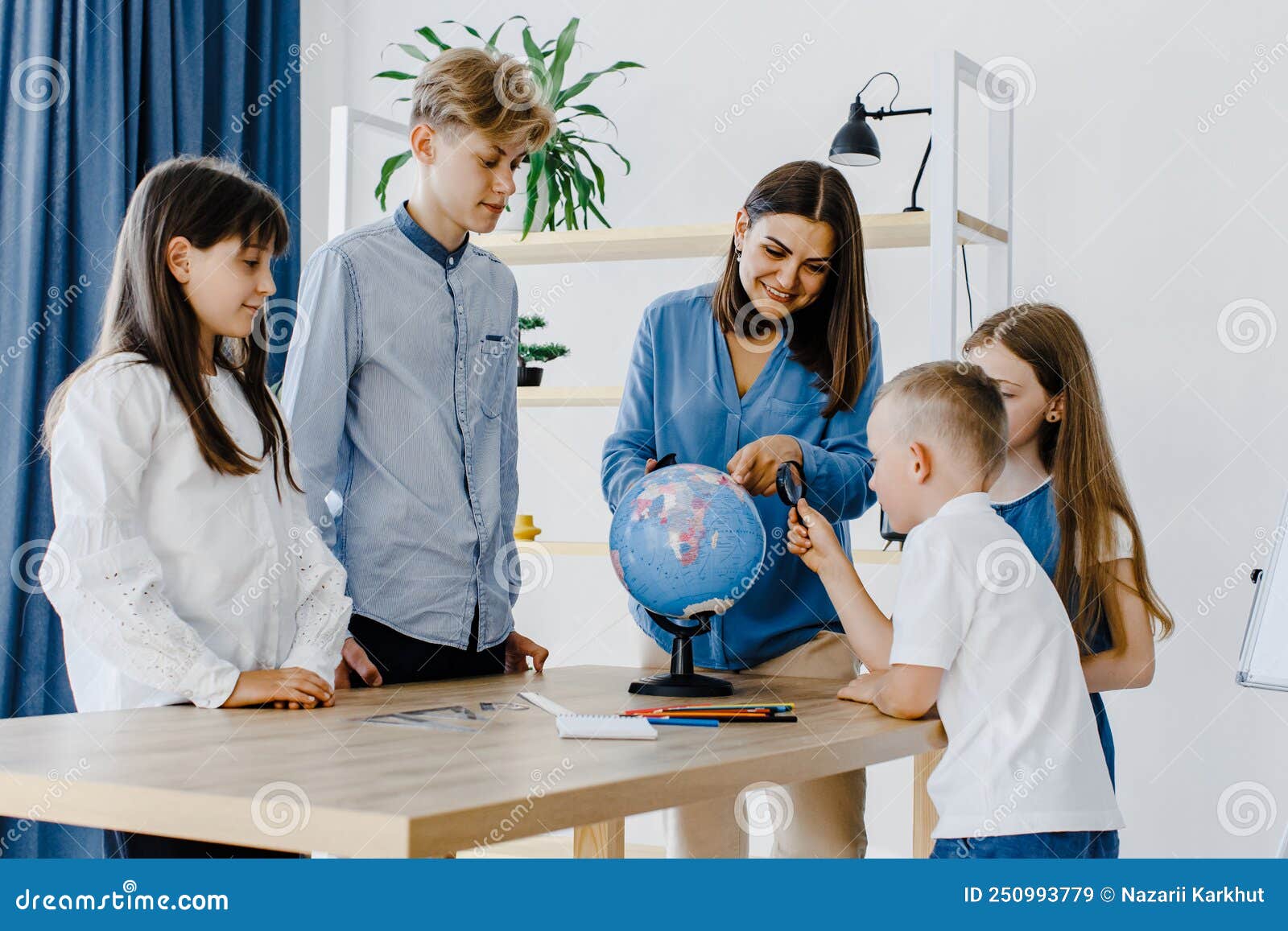 Teacher and Children in Class are Looking at Globe, Teacher Helps ...