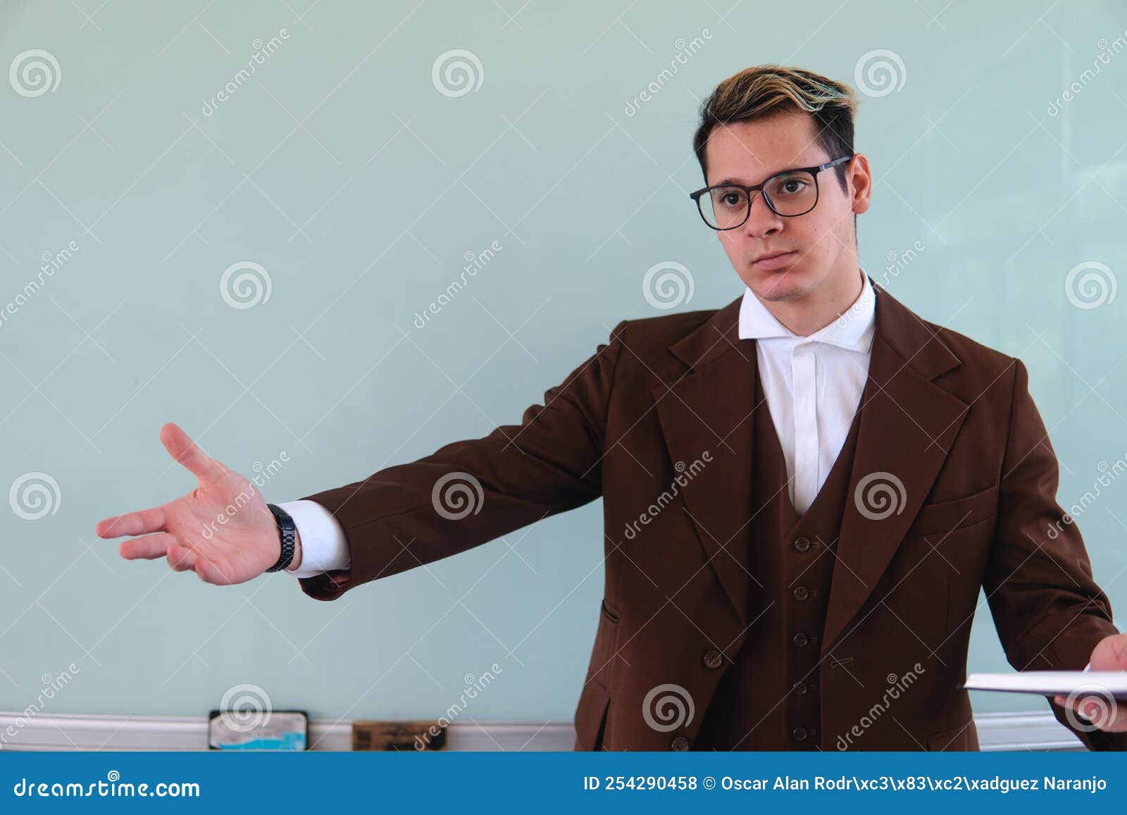 Teacher Dressed in Brown Jacket at a Blackboard with Open Hands ...
