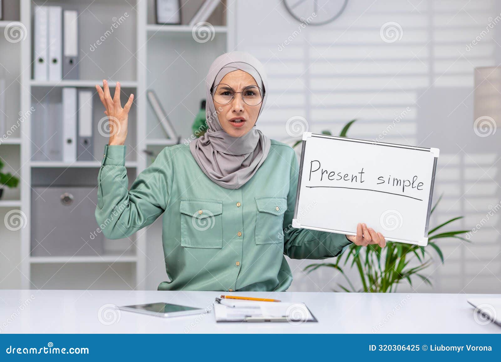 Teacher Explaining Present Simple Tense Holding Whiteboard in Classroom ...