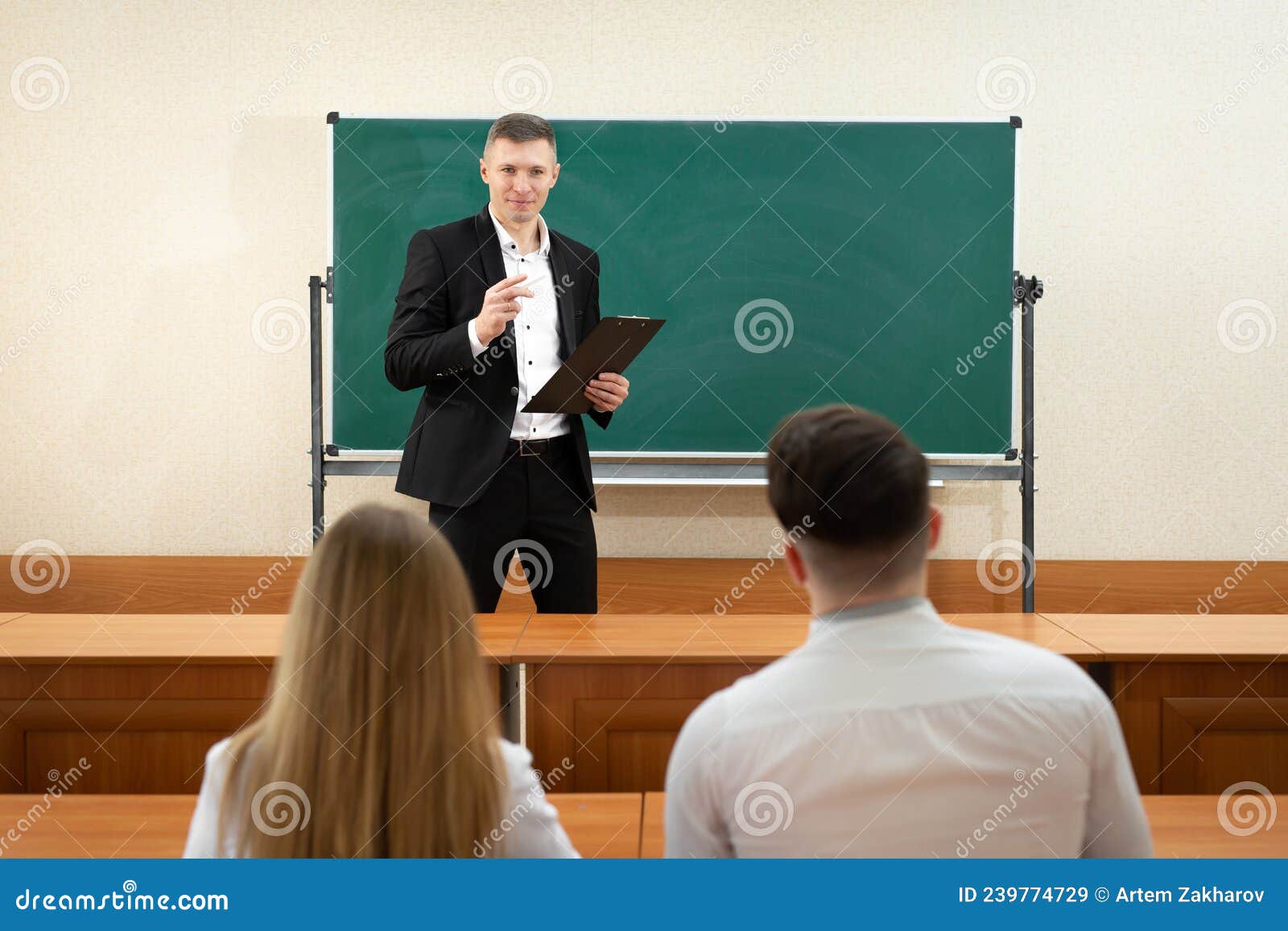 Teacher Giving a Lecture in a Classroom and Writing Math Formulas on ...