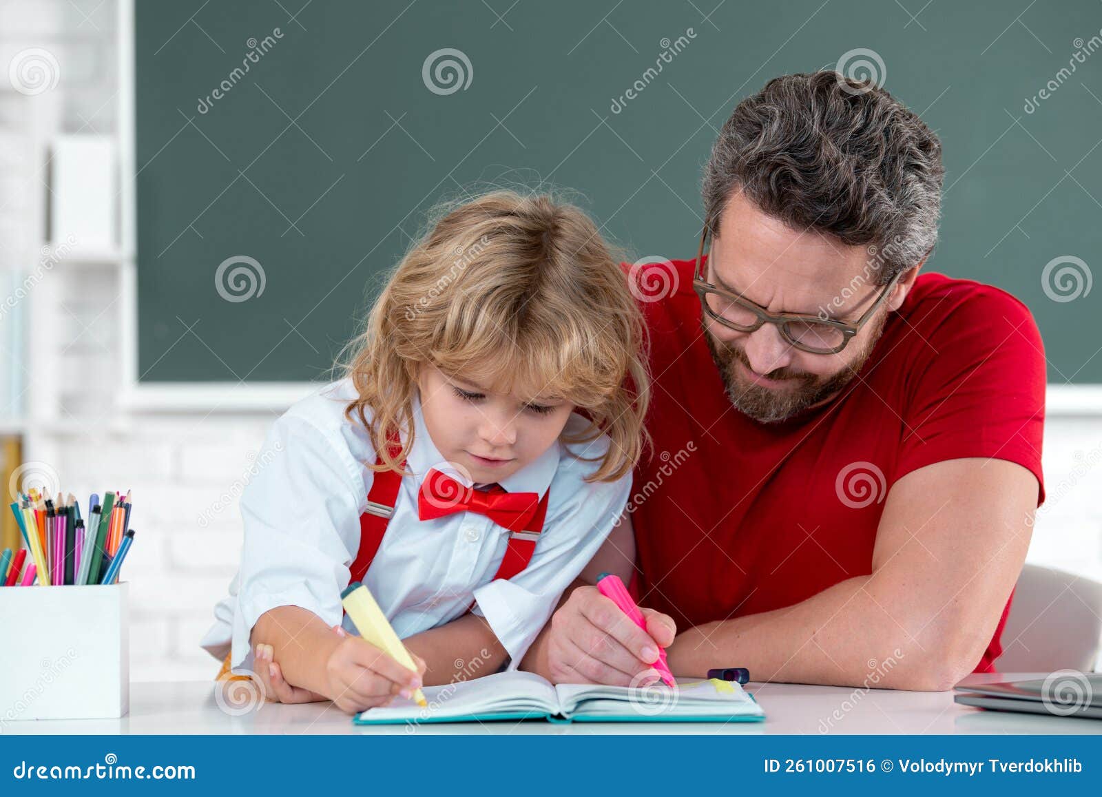 Teacher Helping Child Student Pupil from Elementary School in Classroom ... Teacher Helping Child Student Pupil from Elementary School in Classroom ...