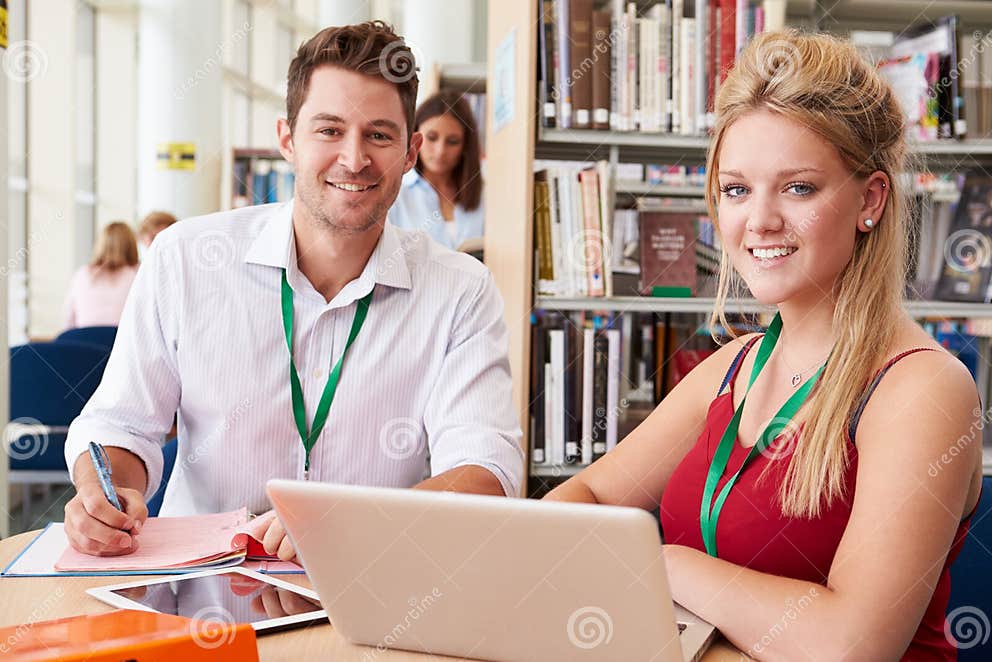 Teacher Helping College Student with Studies in Library Stock Photo ...