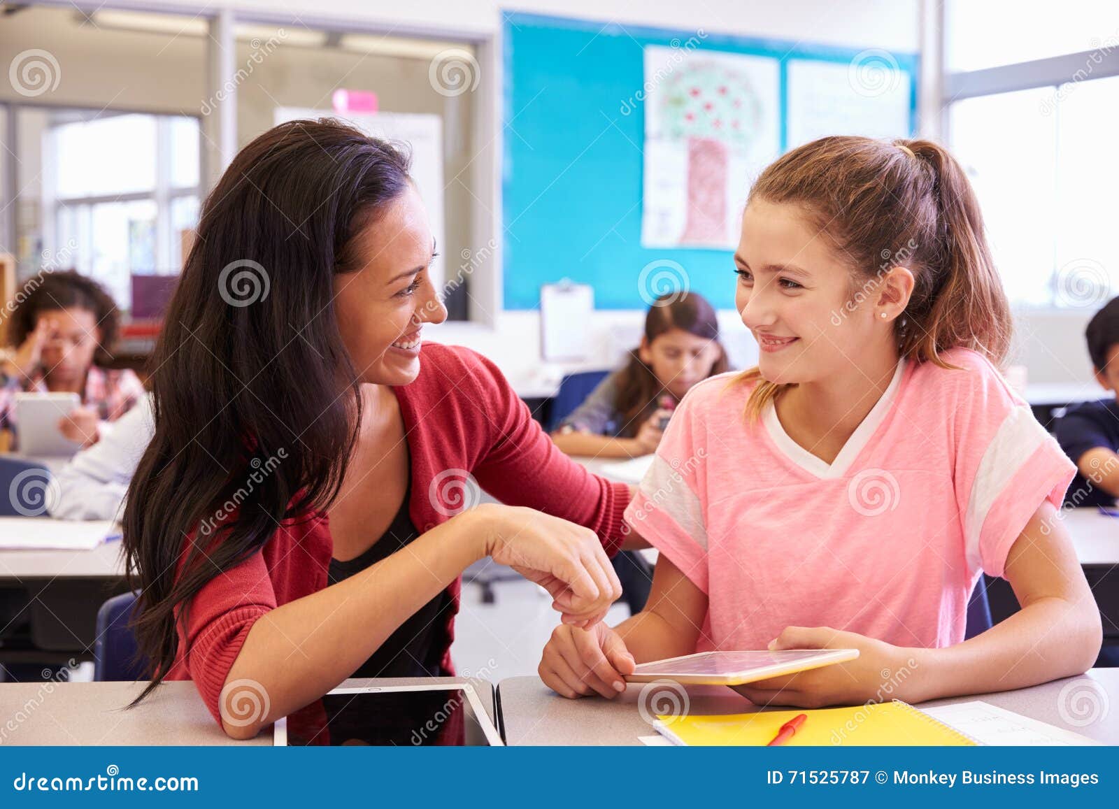Teacher Helping Elementary School Girl Using Tablet Computer Stock ...