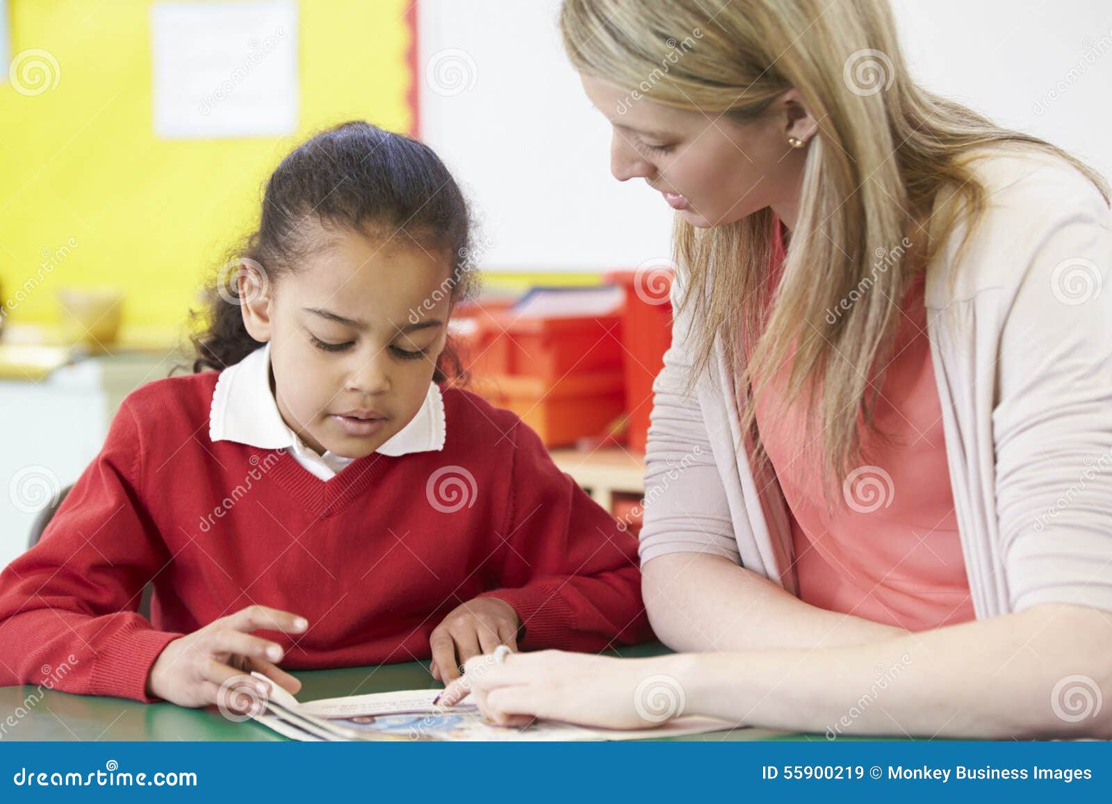 Teacher Helping Female Pupil with Practising Reading at Desk Stock ...