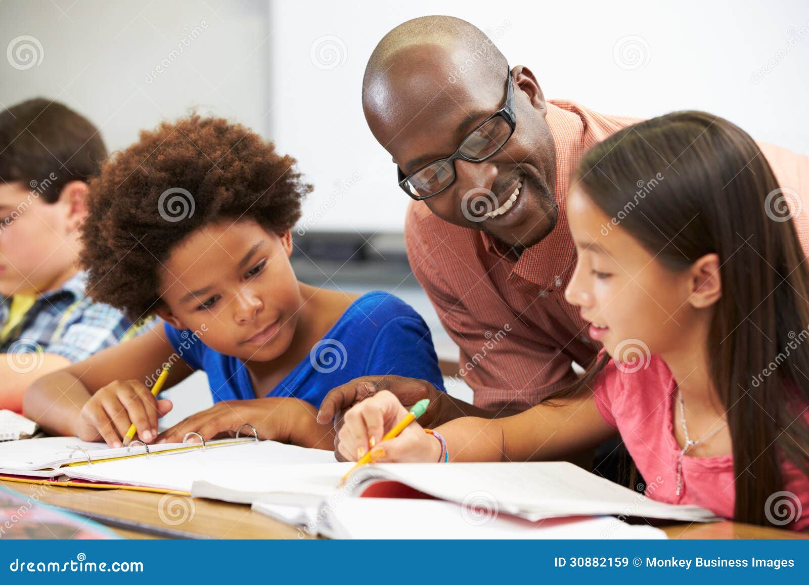 Teacher Helping Pupils Studying at Desks in Classroom Stock Image ...