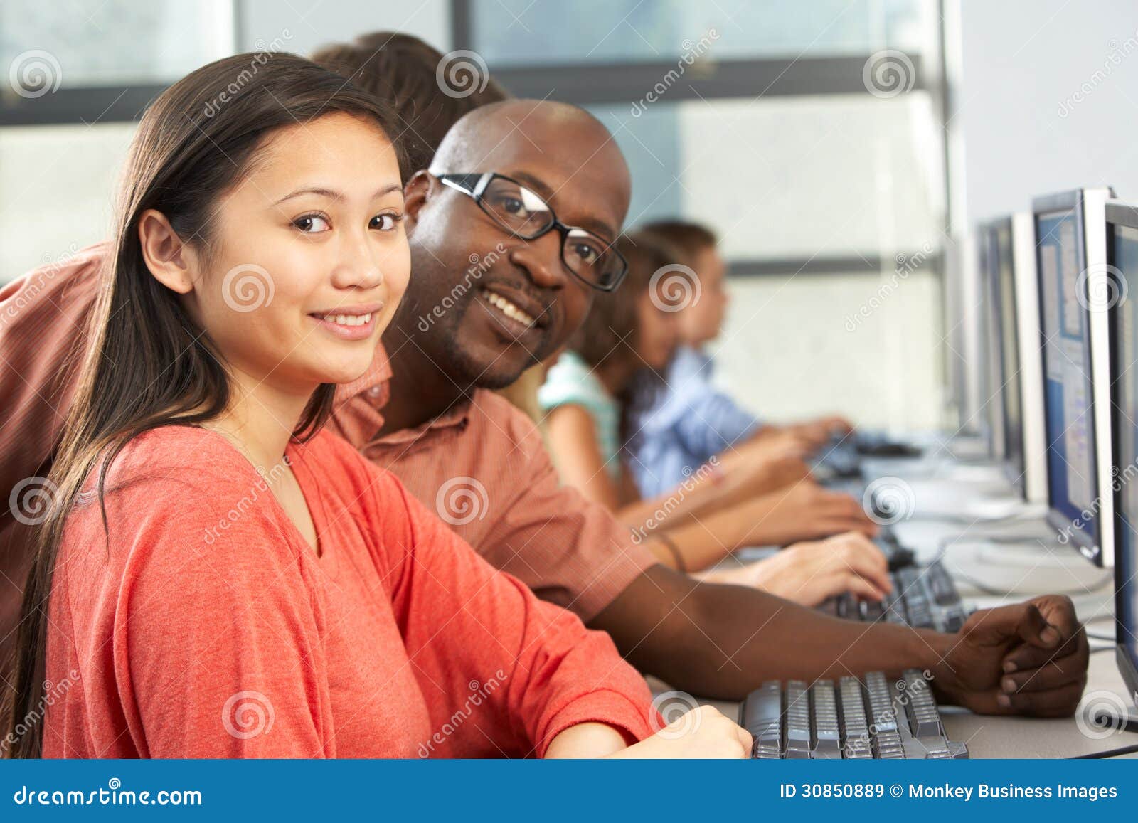 Teacher Helping Students Working at Computers in Classroom Stock Image ...