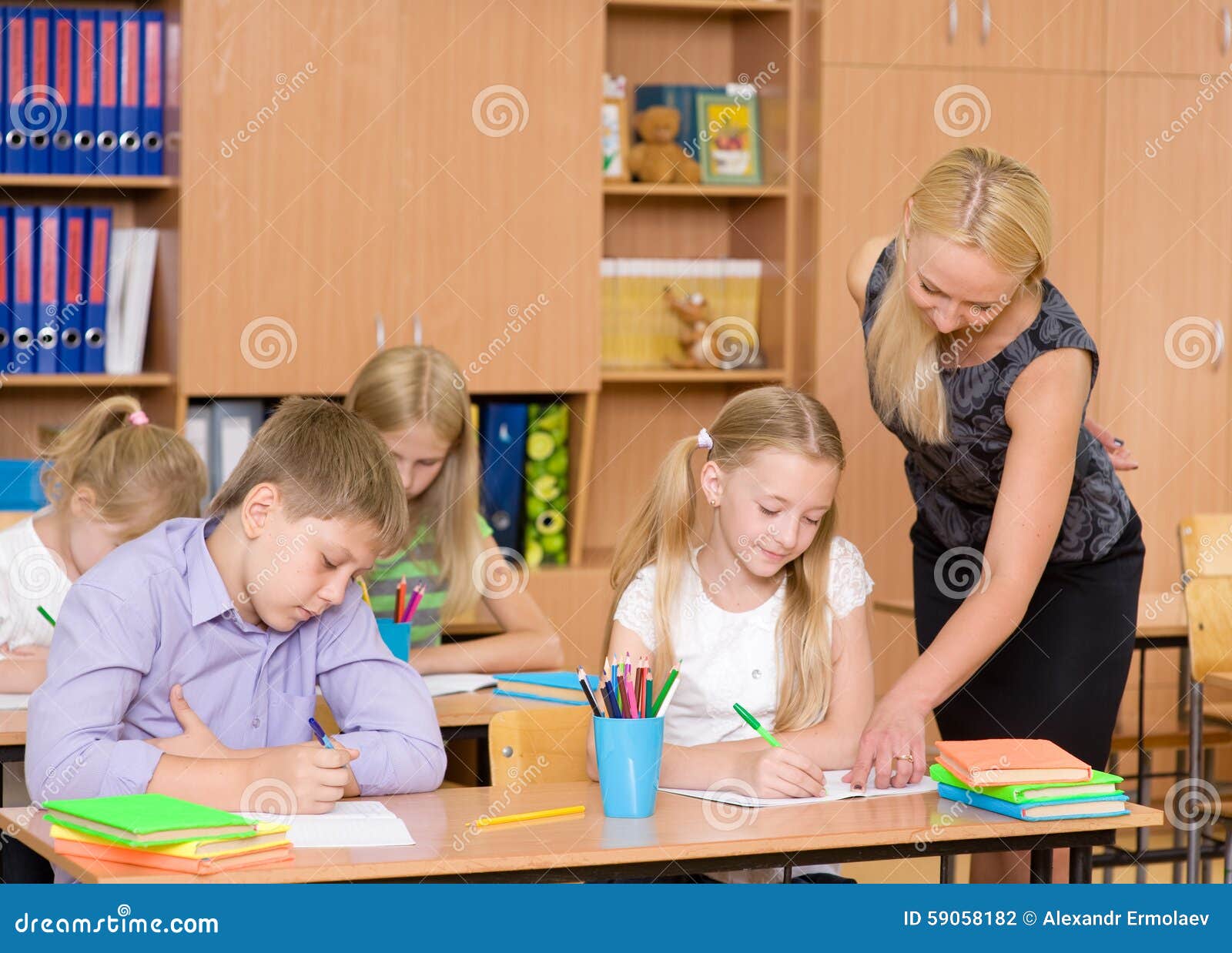The Teacher Helps Schoolgirls In The Lesson, Prompting How To Solve The ... The Teacher Helps Schoolgirls In The Lesson, Prompting How To Solve The ...