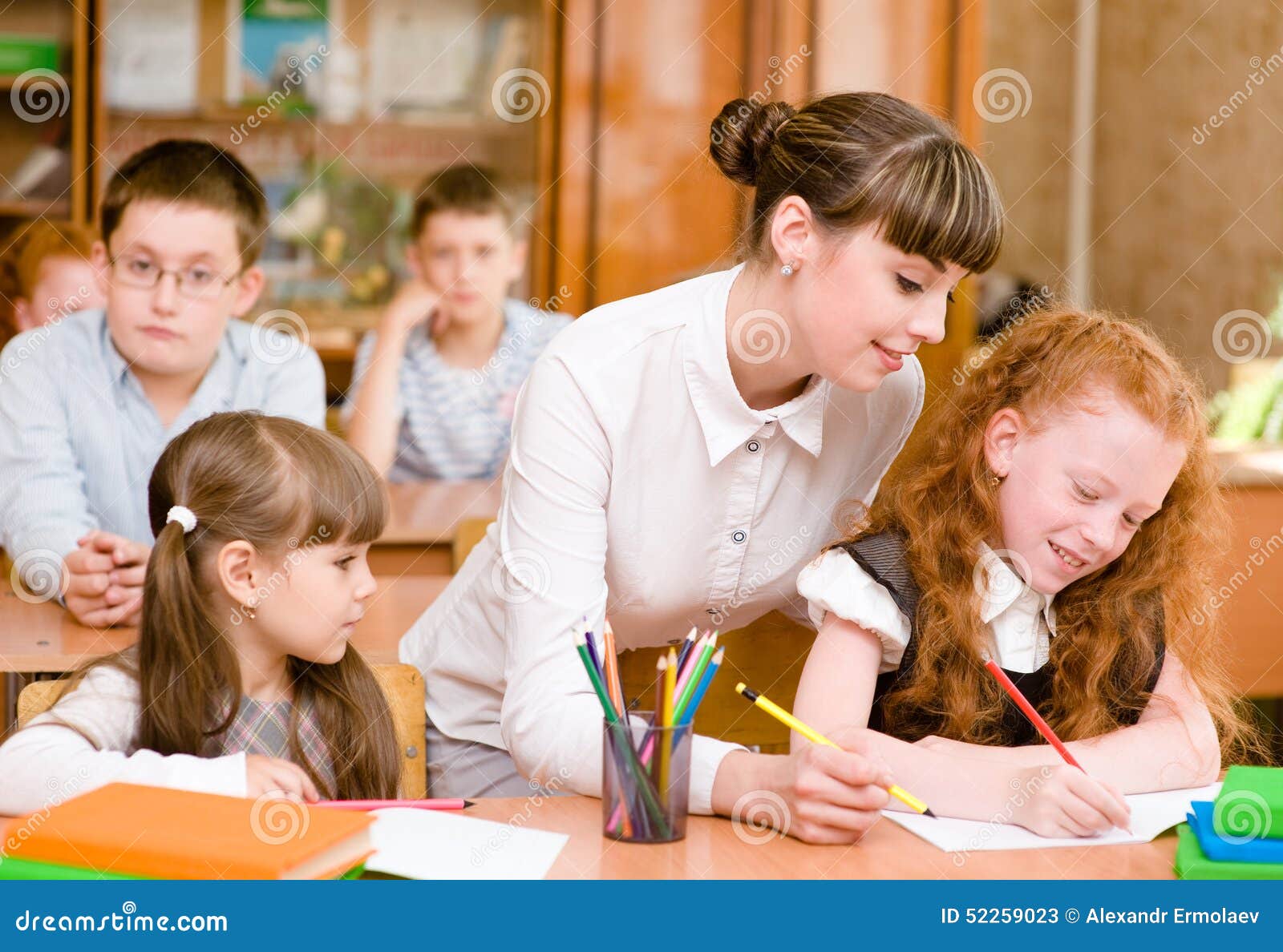 The Teacher Helps Schoolgirls In The Lesson, Prompting How To Solve The ... The Teacher Helps Schoolgirls In The Lesson, Prompting How To Solve The ...